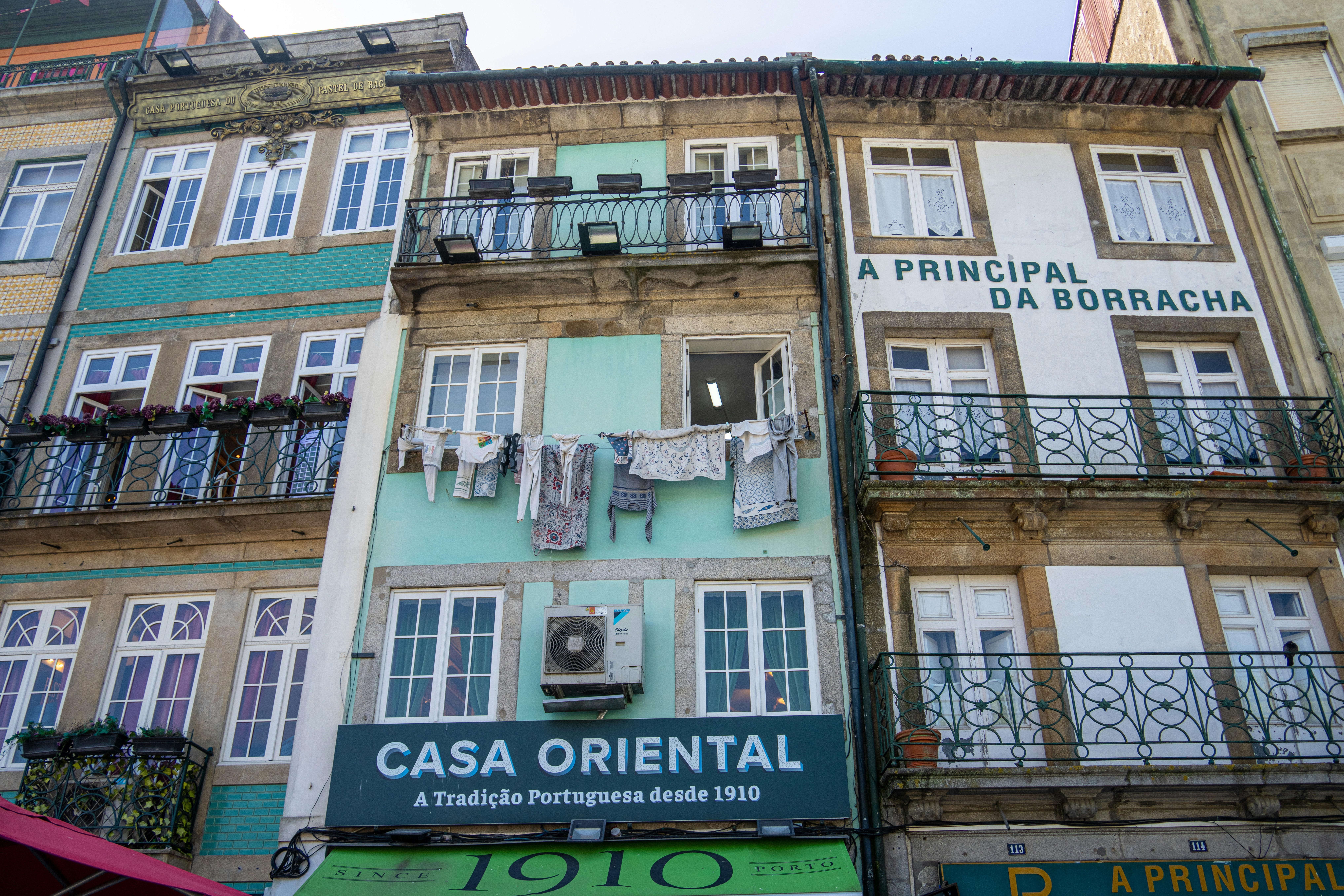 Casa Oriental on a sunlit Portuguese street, with laundry hung between colorful façades