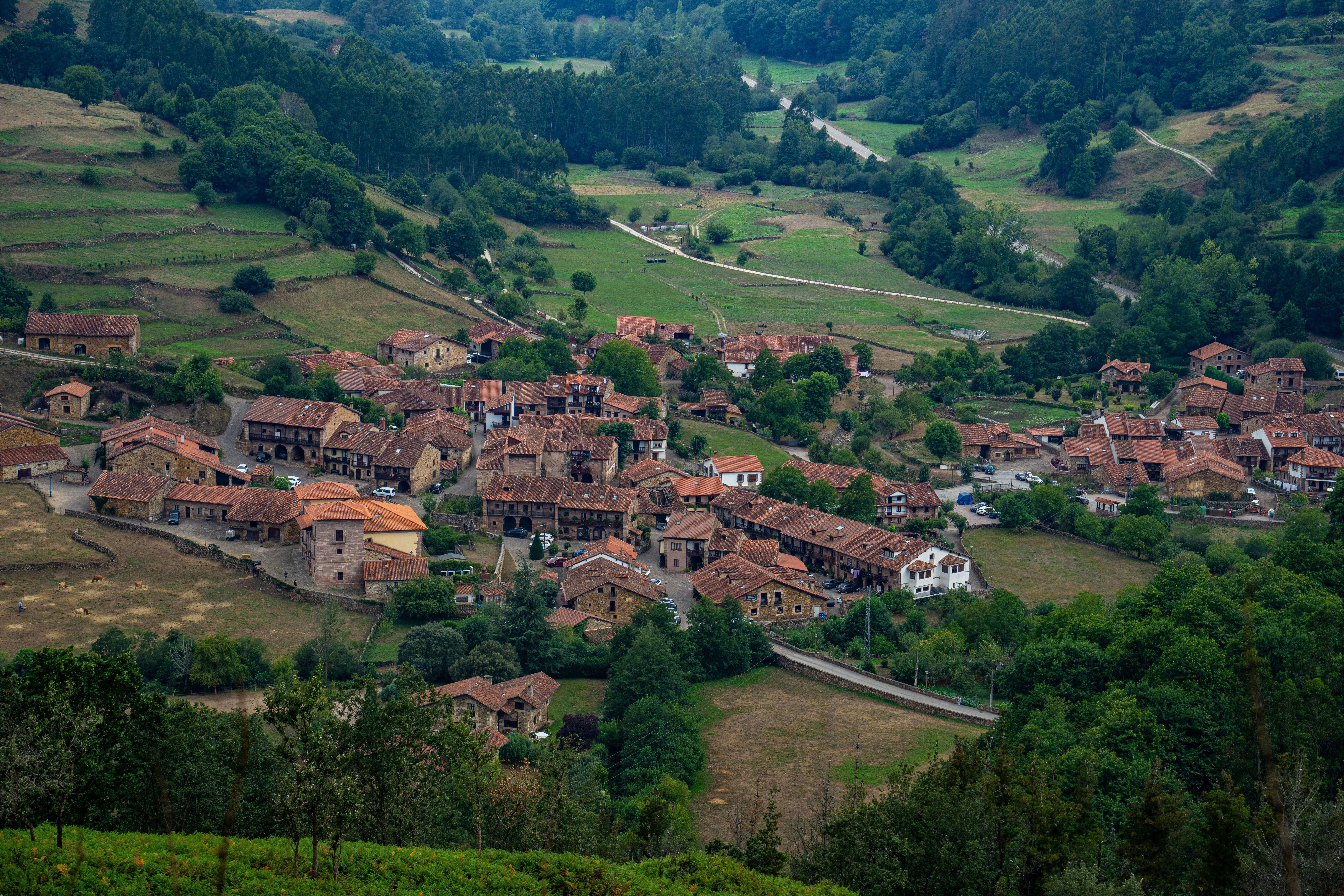 Terraced Village Spill: Red-roofed Homes Nestle in Emerald Valleys