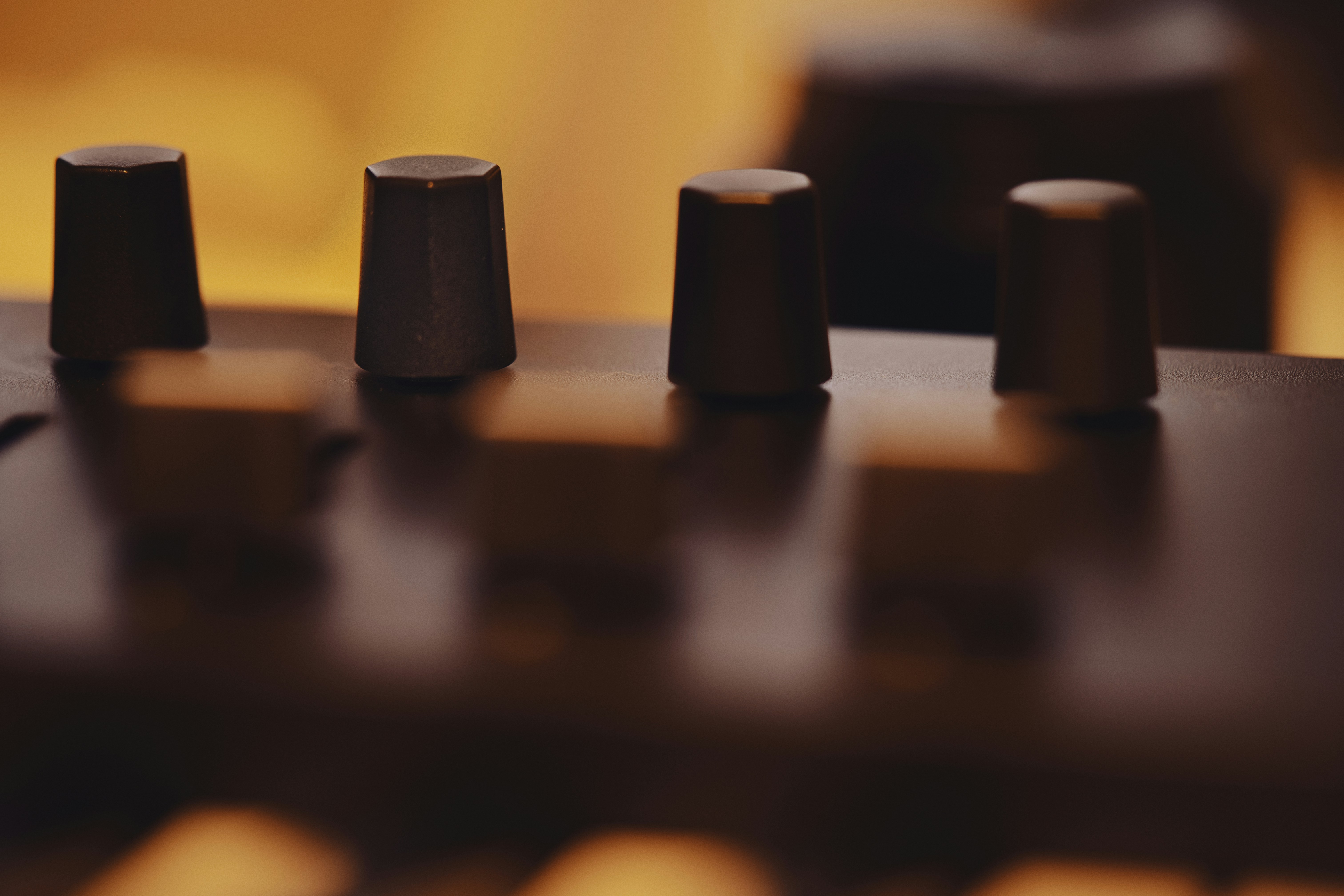 Warm-toned Synth: Close-up of Blurred Knobs on a Dark Console