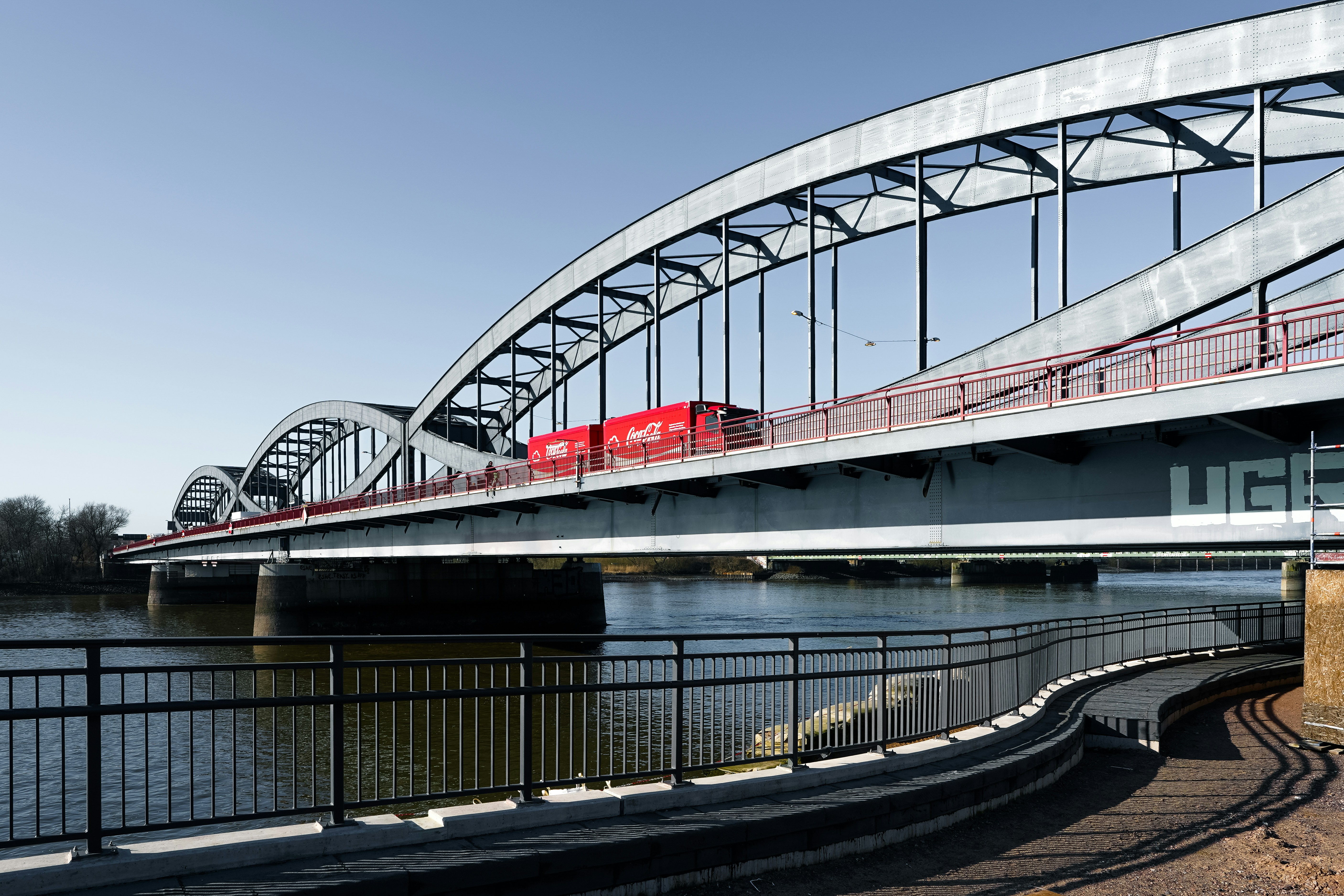 Curved steel lifeline: a riverside arch bridges its morning