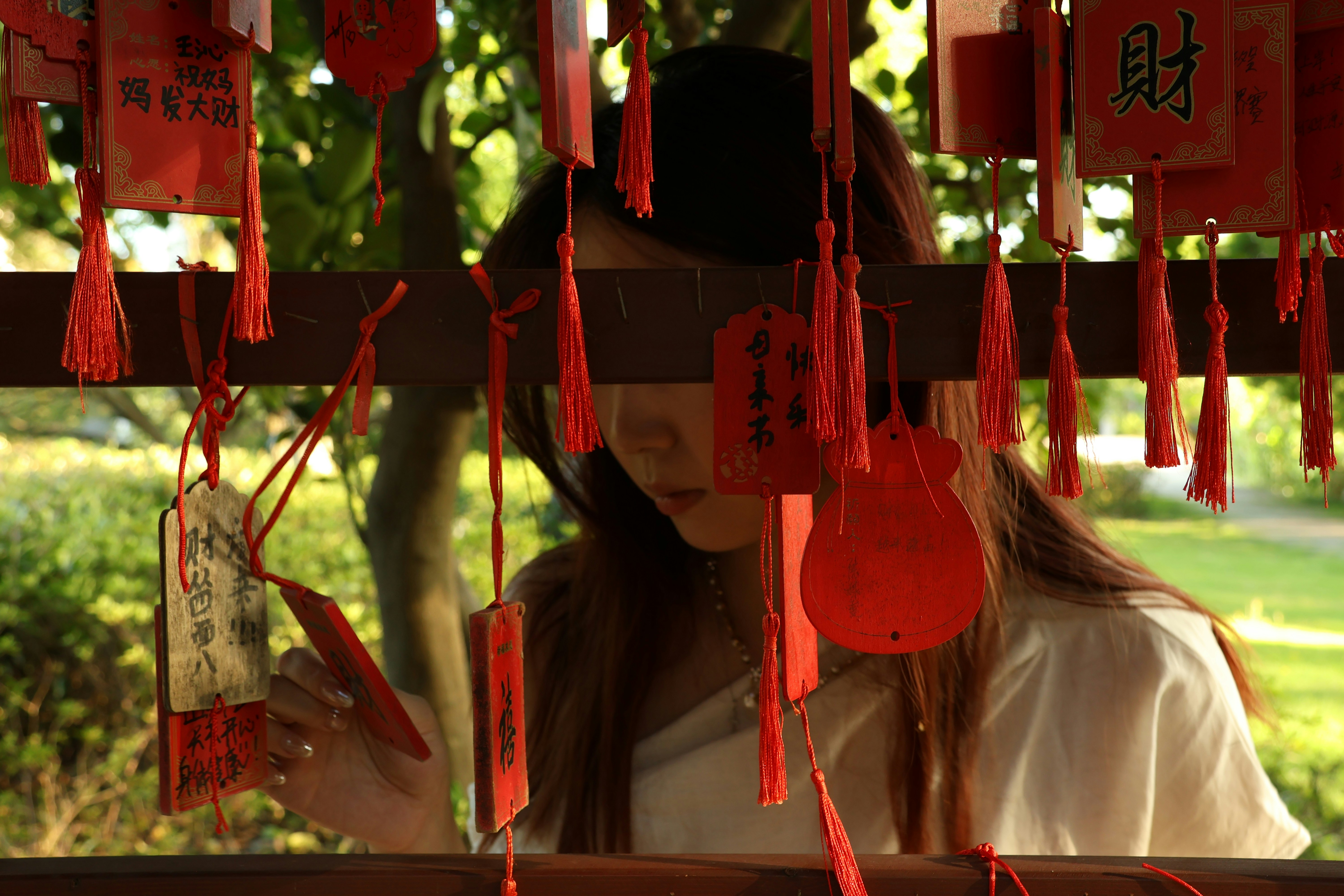 Red Strings, Quiet Focus: A Soft Portrait Beneath Sacred Ornaments