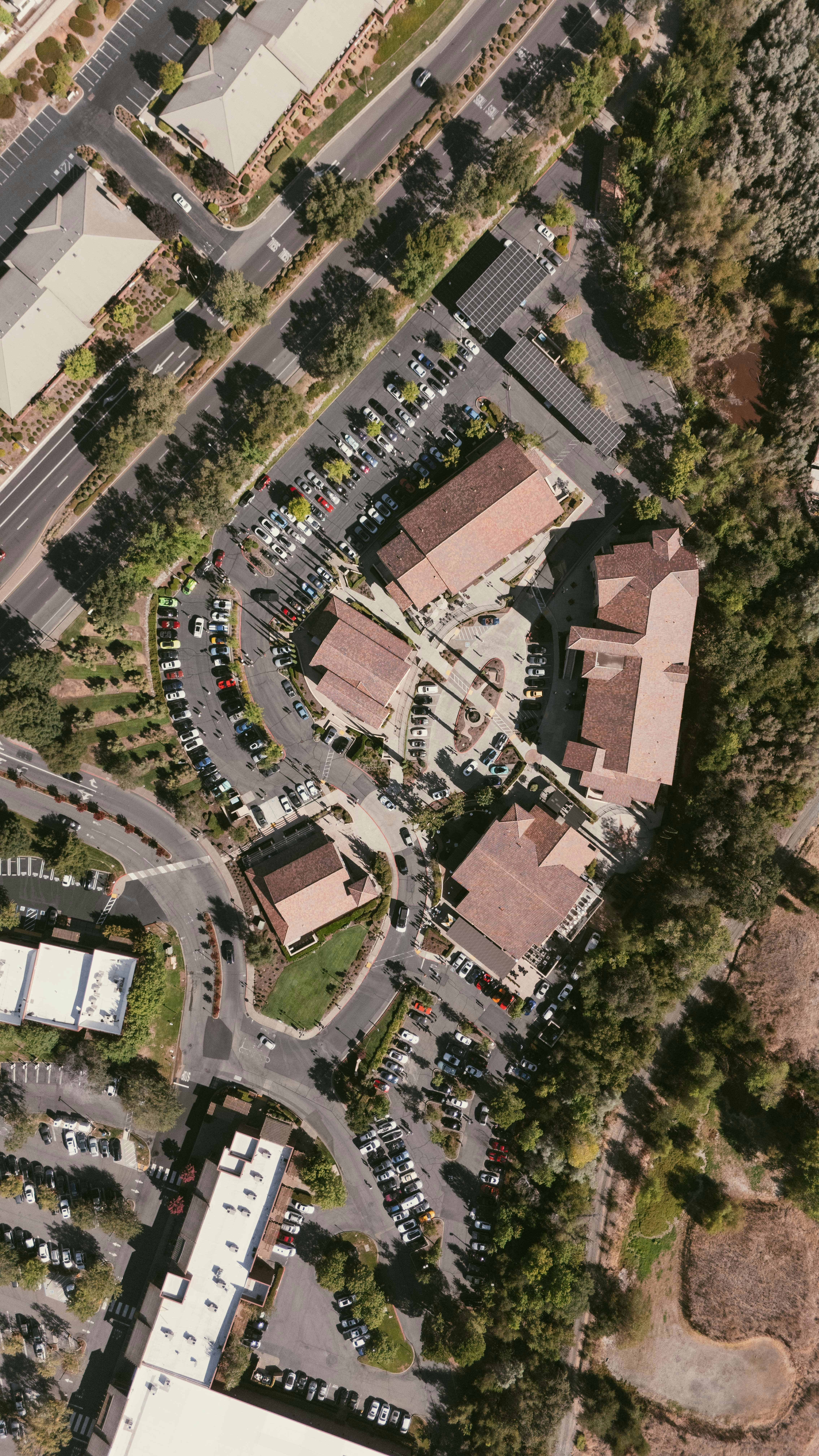 Aerial View Over a Curved Parking Complex and Campus Buildings