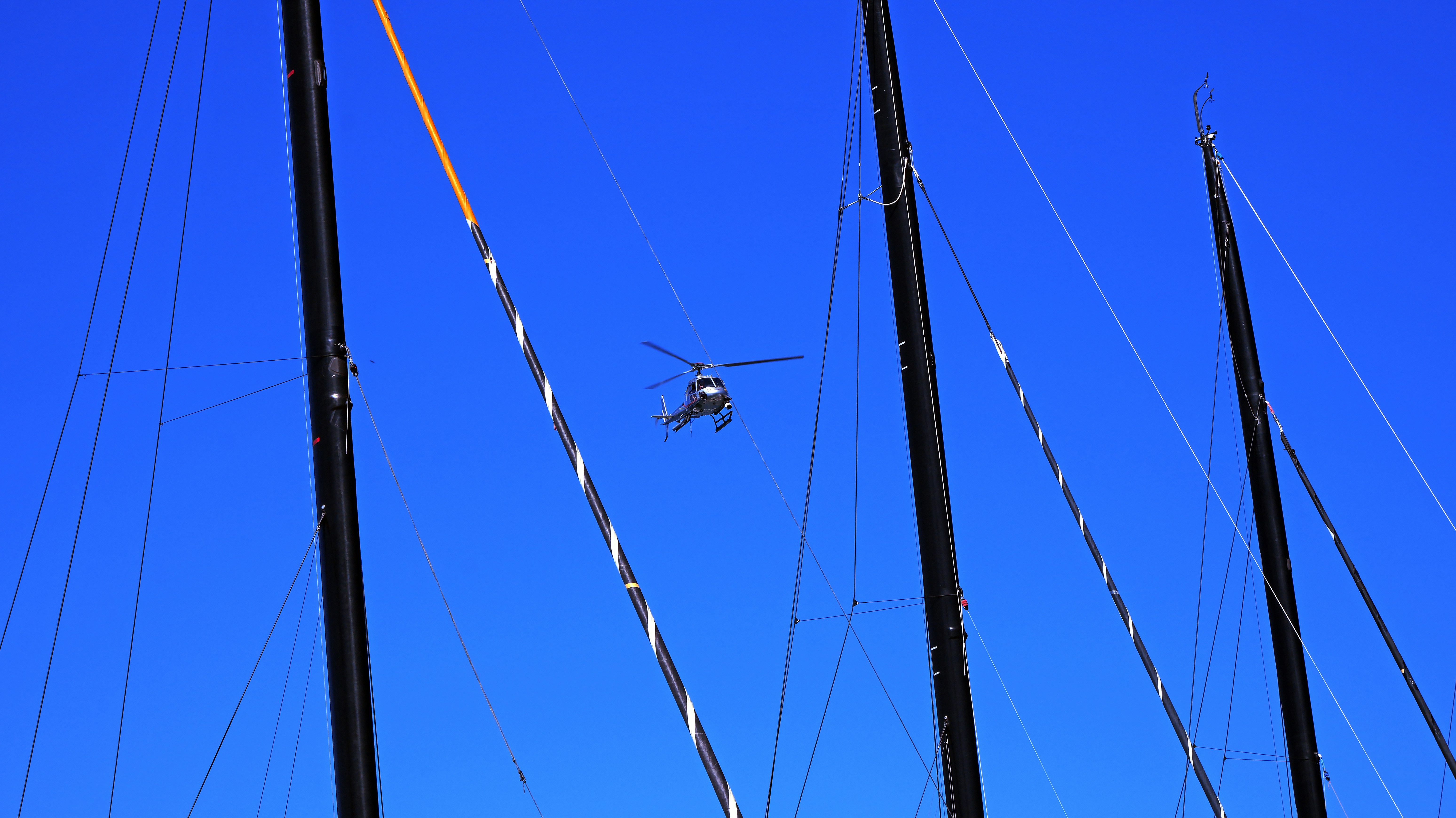 Helm in the Sky: A Drone's Eye on Sails and Cables Against a Clear Blue