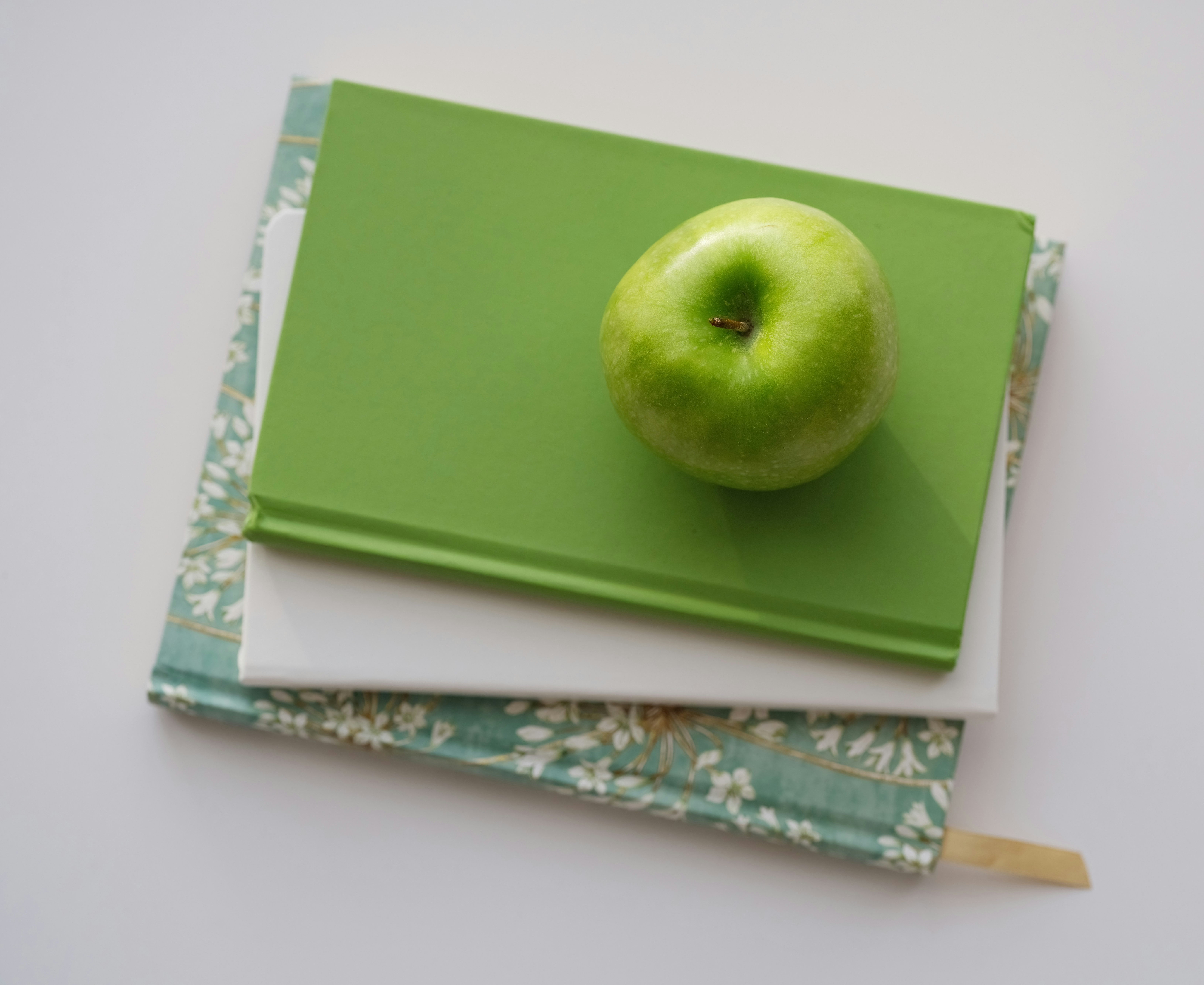 Green Apple on Top of a Stack: Quiet StillLife with Patterned Notebook
