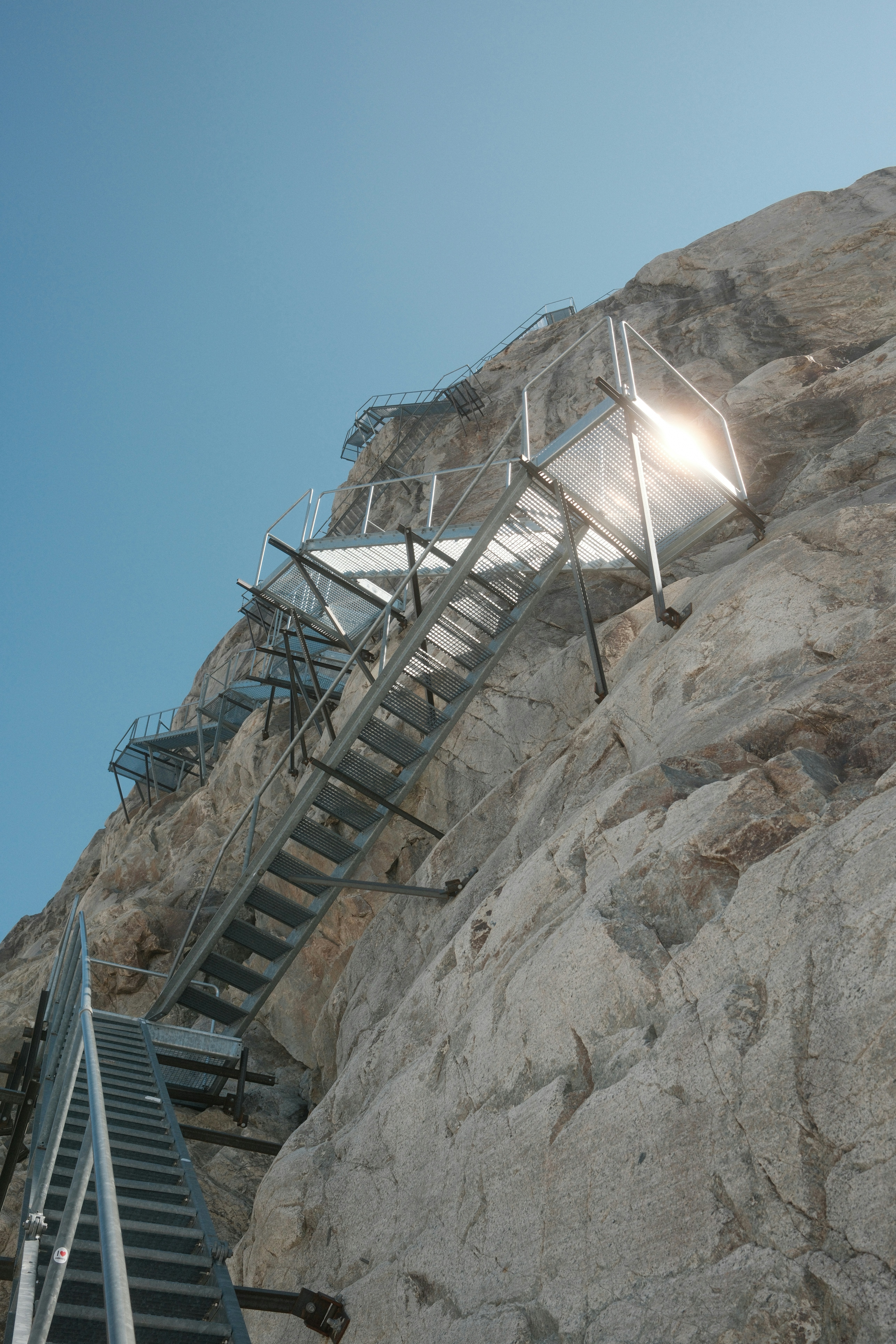 Metal Staircase Climbing a Cliff Under a Bright Sky
