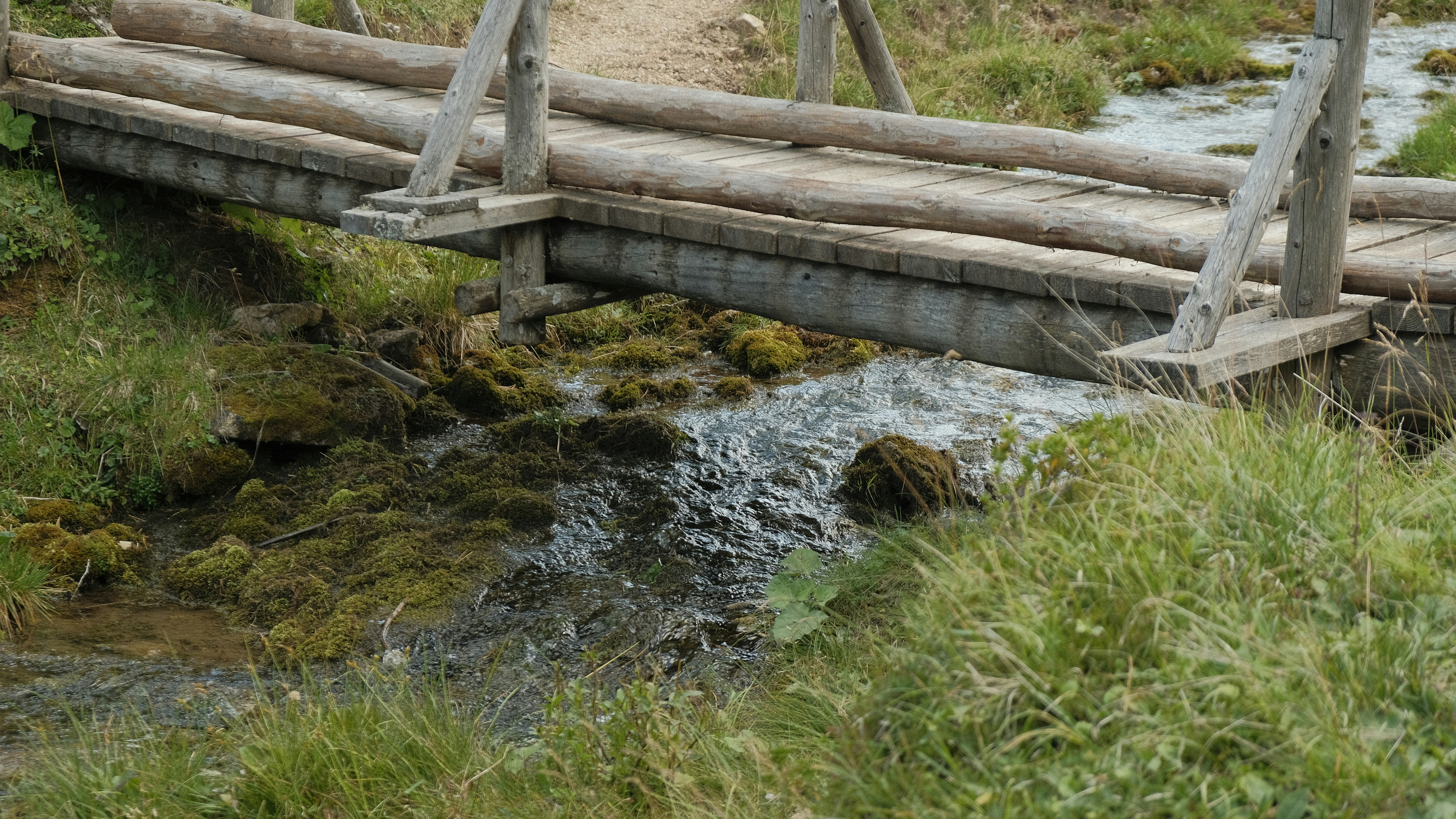 Bridge Over a Quiet Stream: Weathered Wood and Mossy Stones