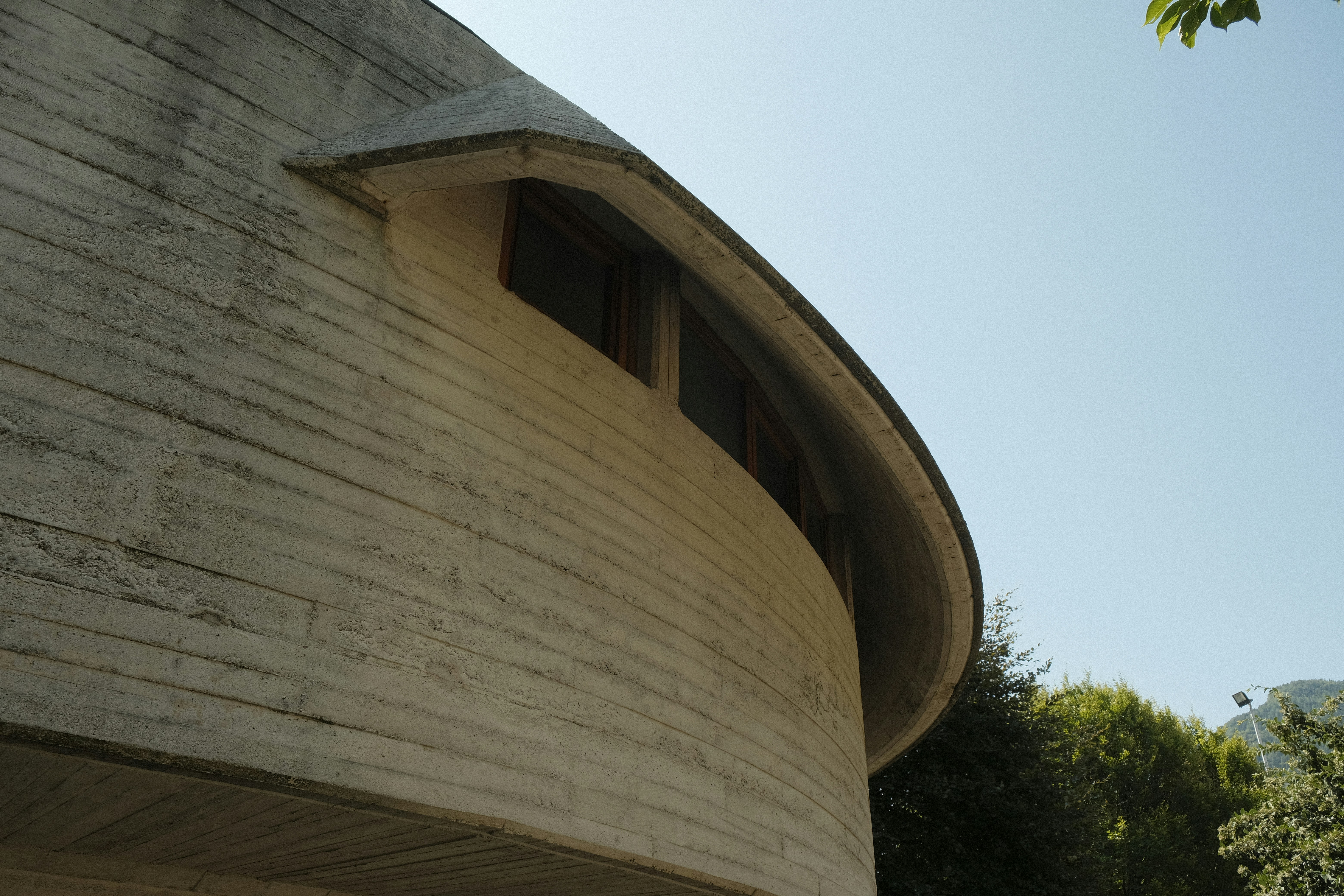 Curve of Concrete: A Circular Building Against a Clear Sky