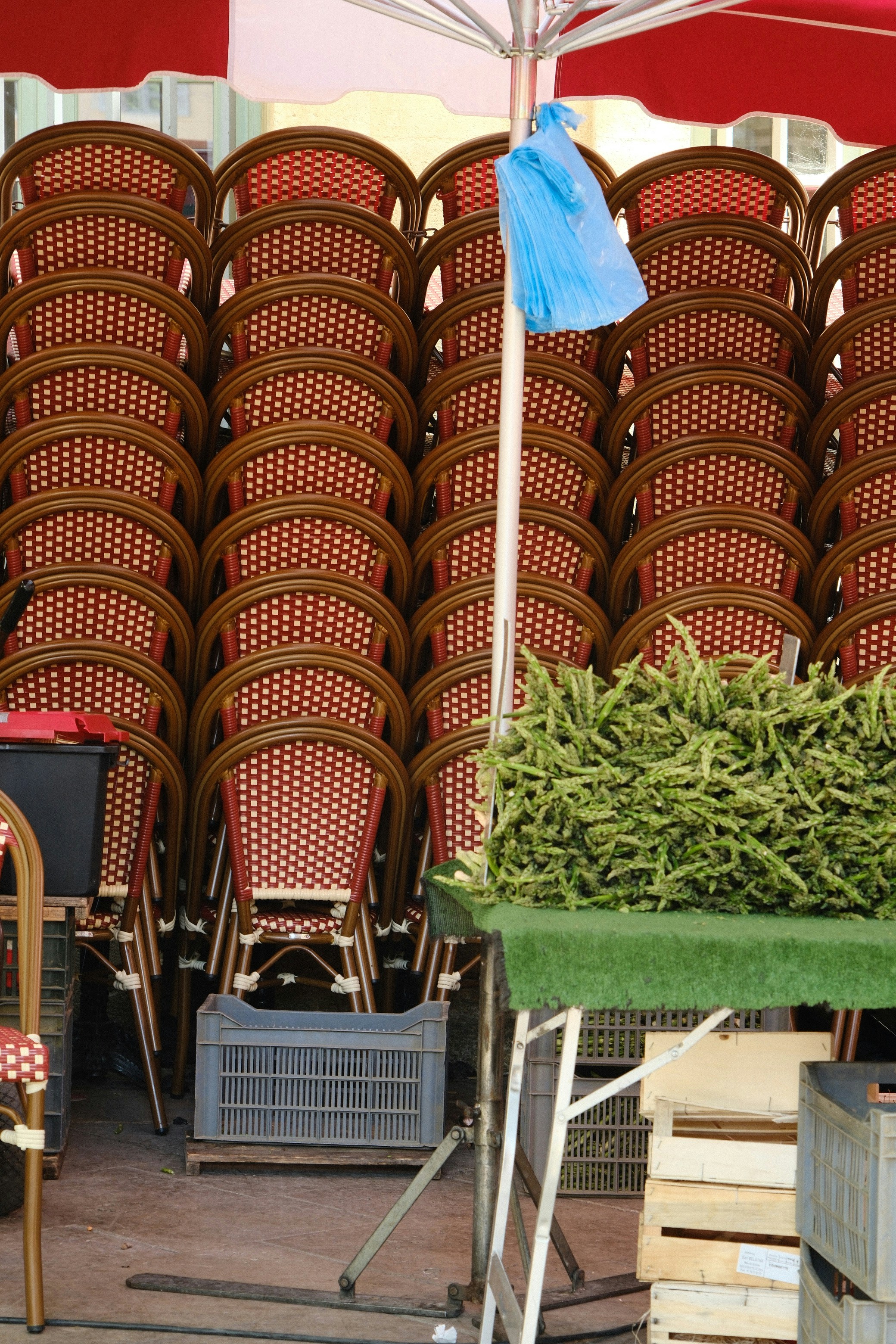Stacked Chairs behind a Market Stall with Fresh Greenery