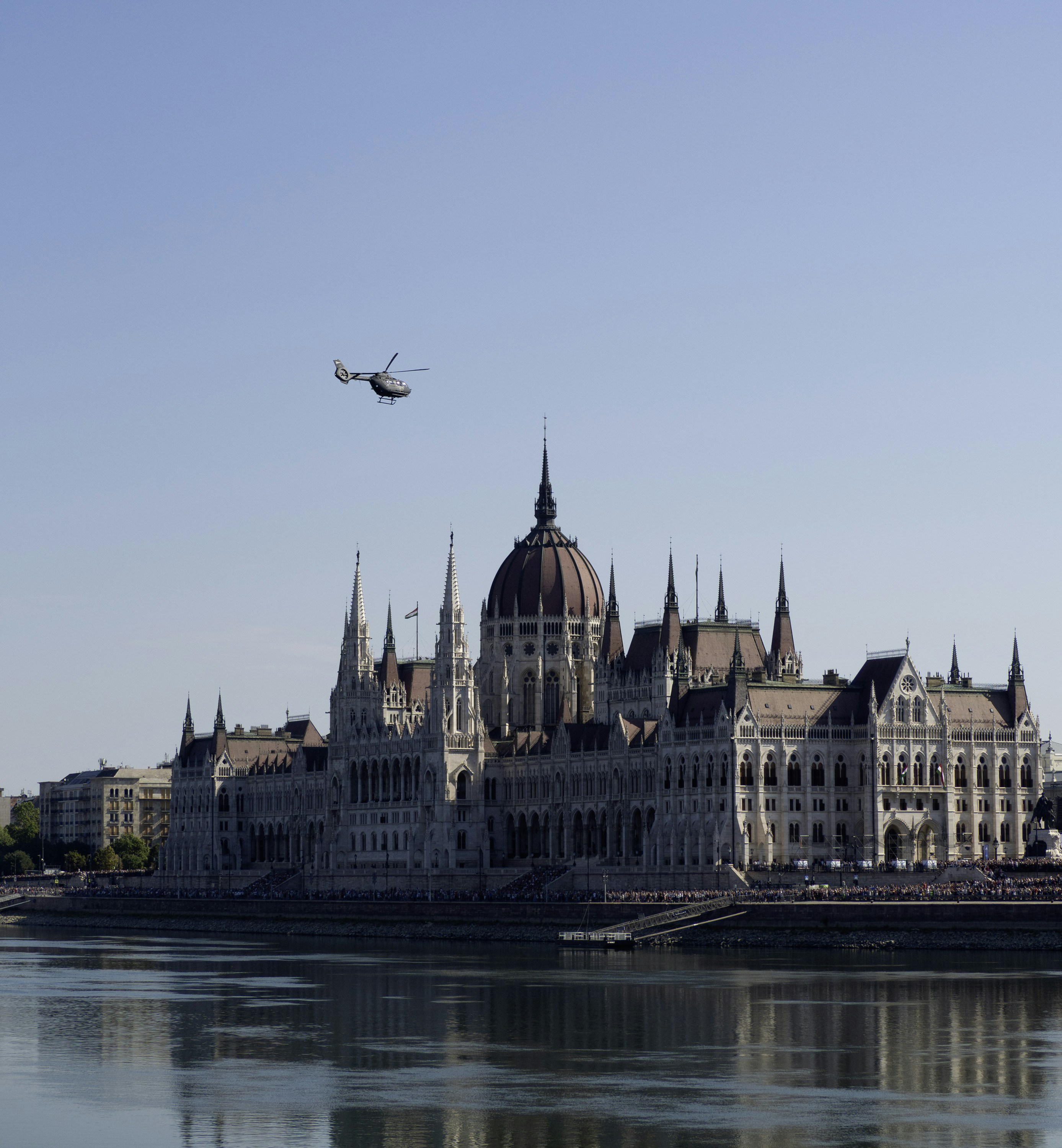 Airborne Sentinel Over the Danube: A Helicopter Bids Hungary’s Parliament Adorned Skyline