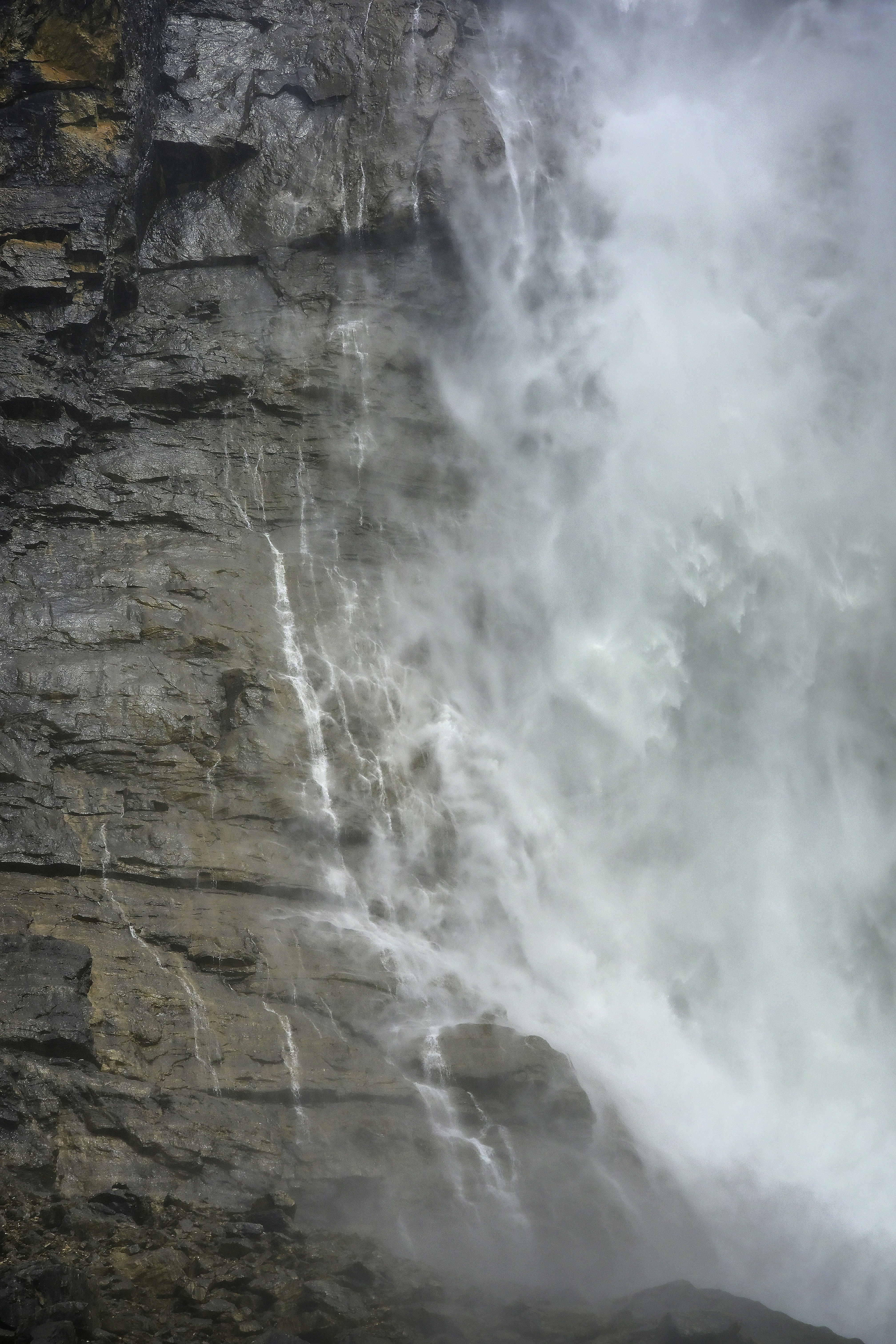 Thundering waterfall carved into rugged rock, with mist rising and water cascading down a sheer cliff.