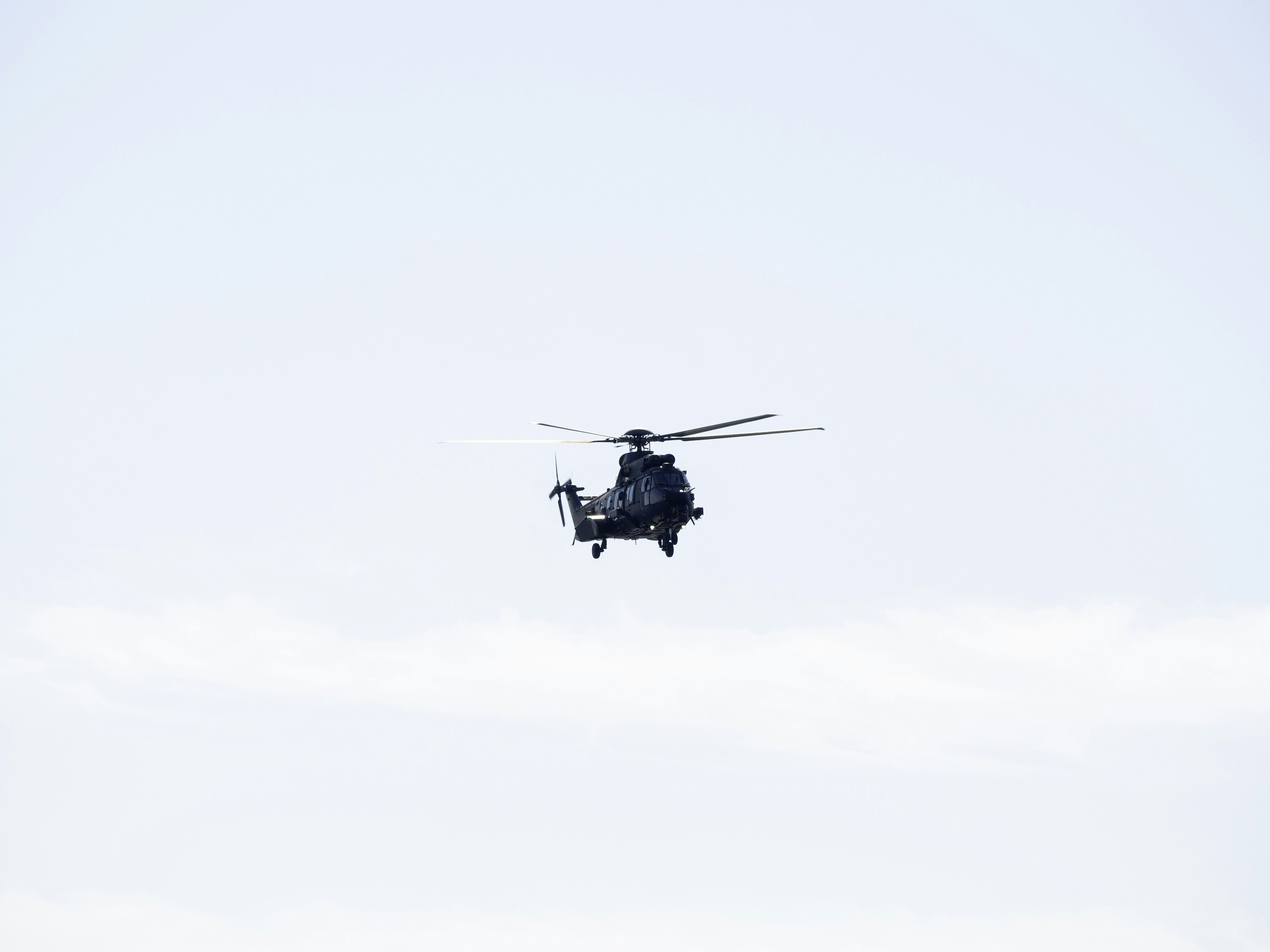 Midair Sentinel: a lone helicopter hovering above pale clouds