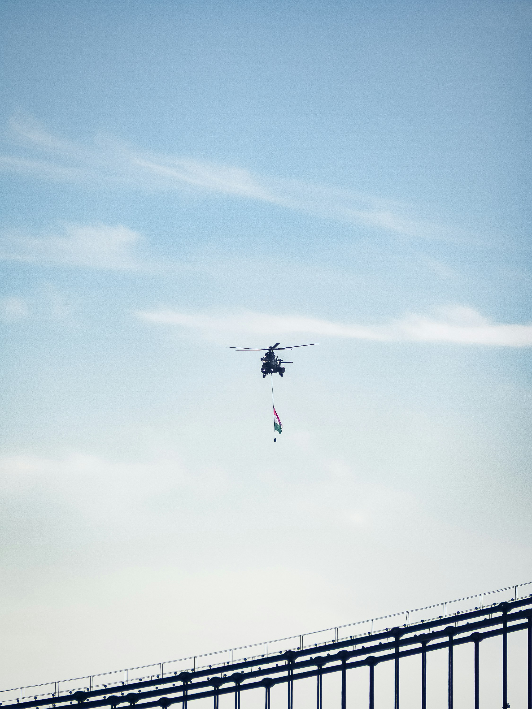 Helicopter Ascend with Flag over a Bridge, Skies Opening Ahead