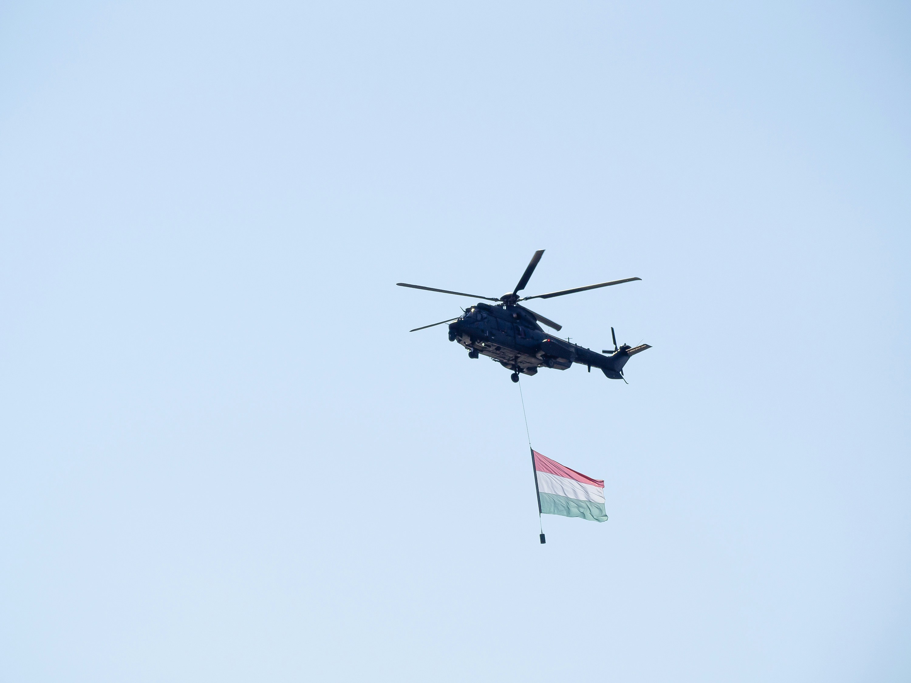 Flag Descends from a Helicopter in Clear Sky