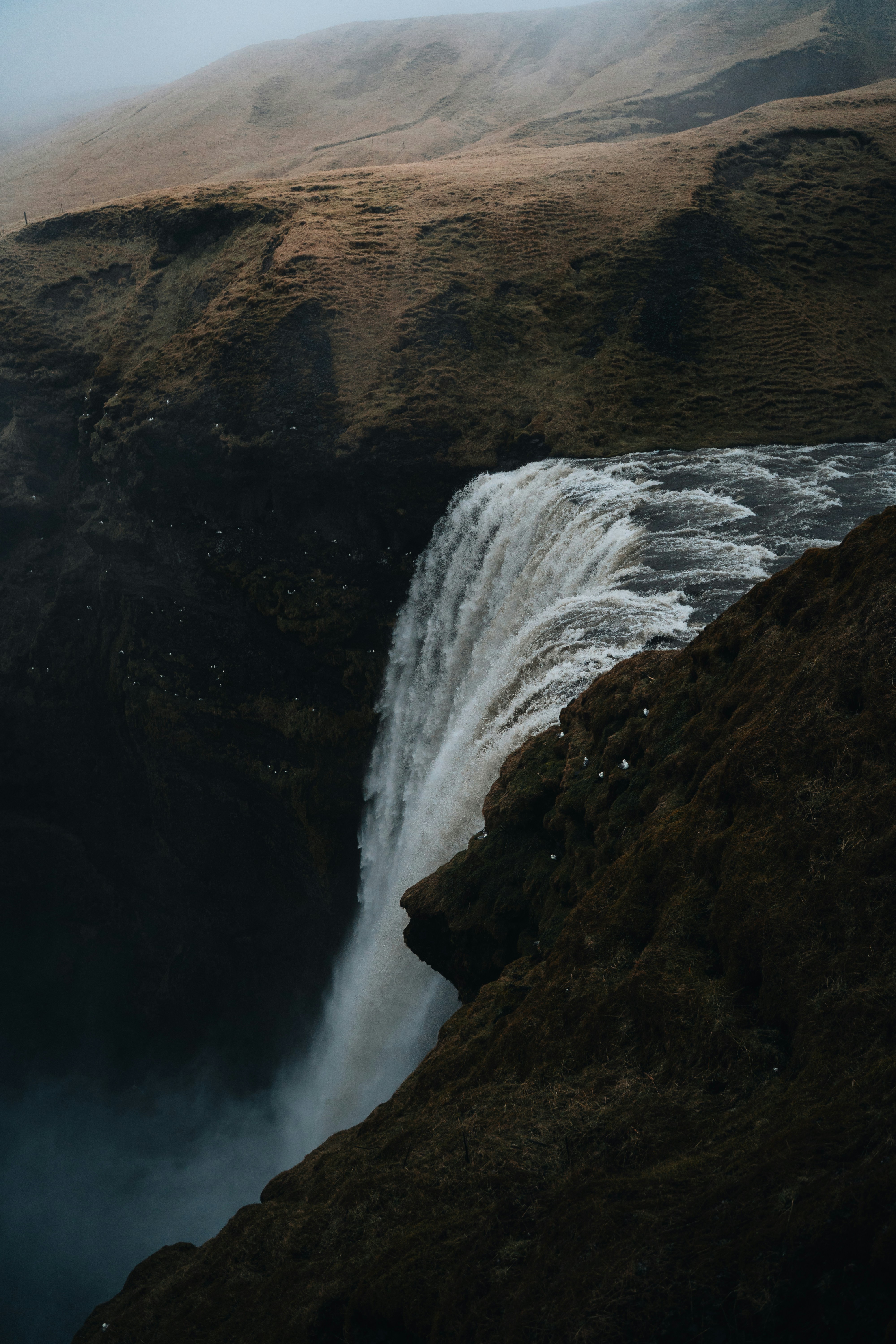 Cascading Edge: A Dramatic Cliffside Waterfall Plunging into Shadowed Depths