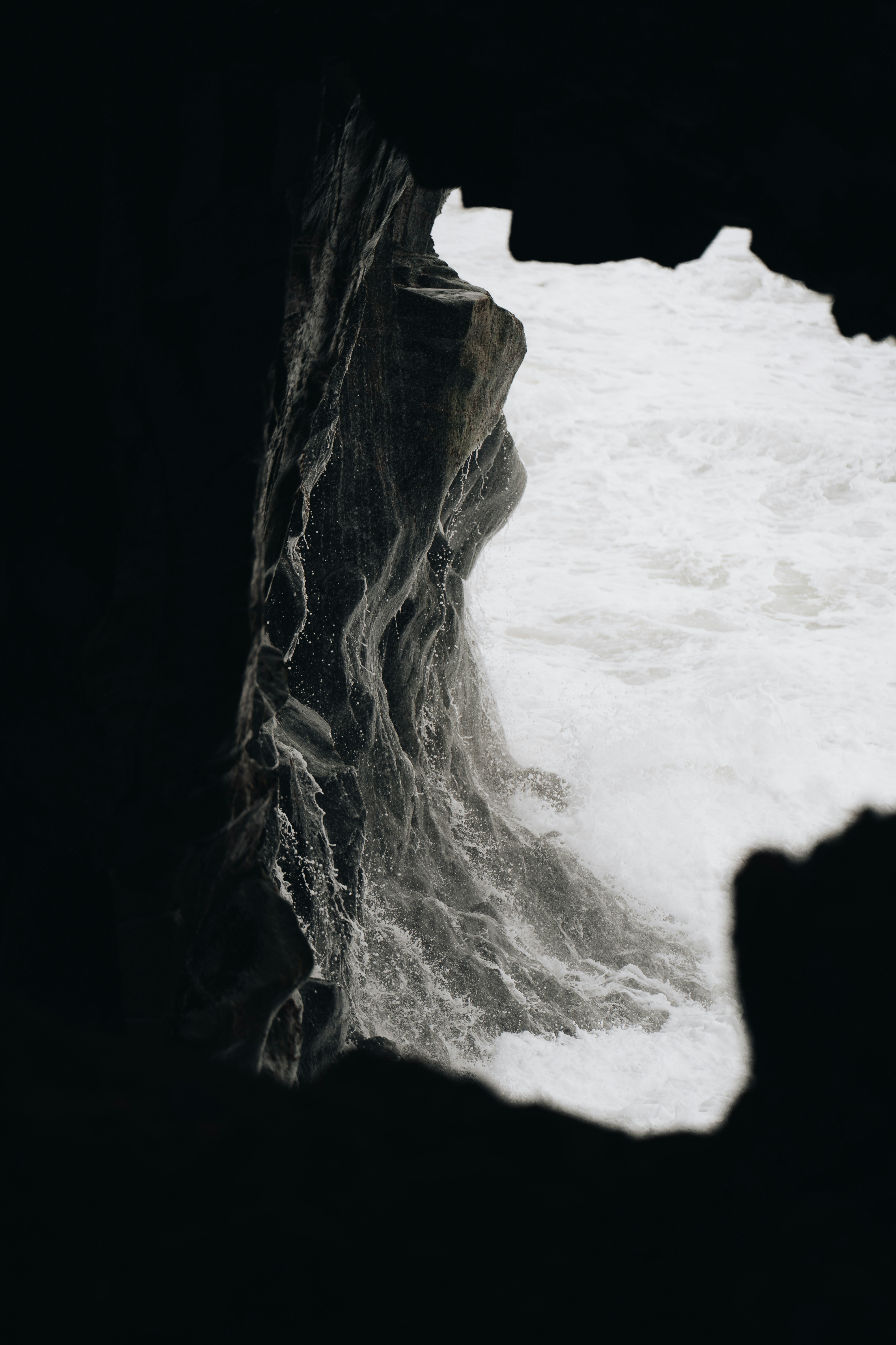 Coastline Veil: Waves Carving a Dark Cliff Cave