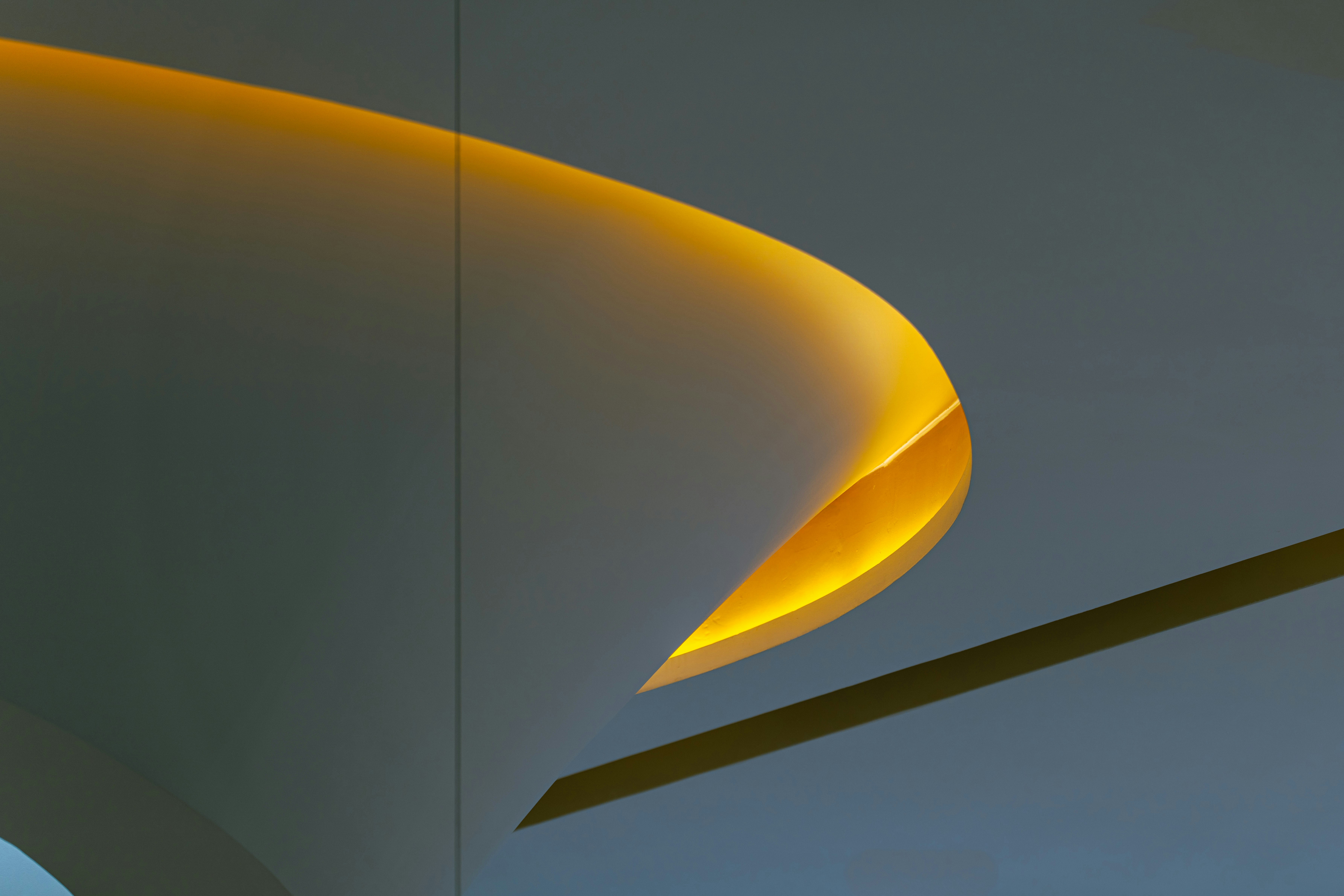 Curved light and shadow: a golden arc against cool geometry
