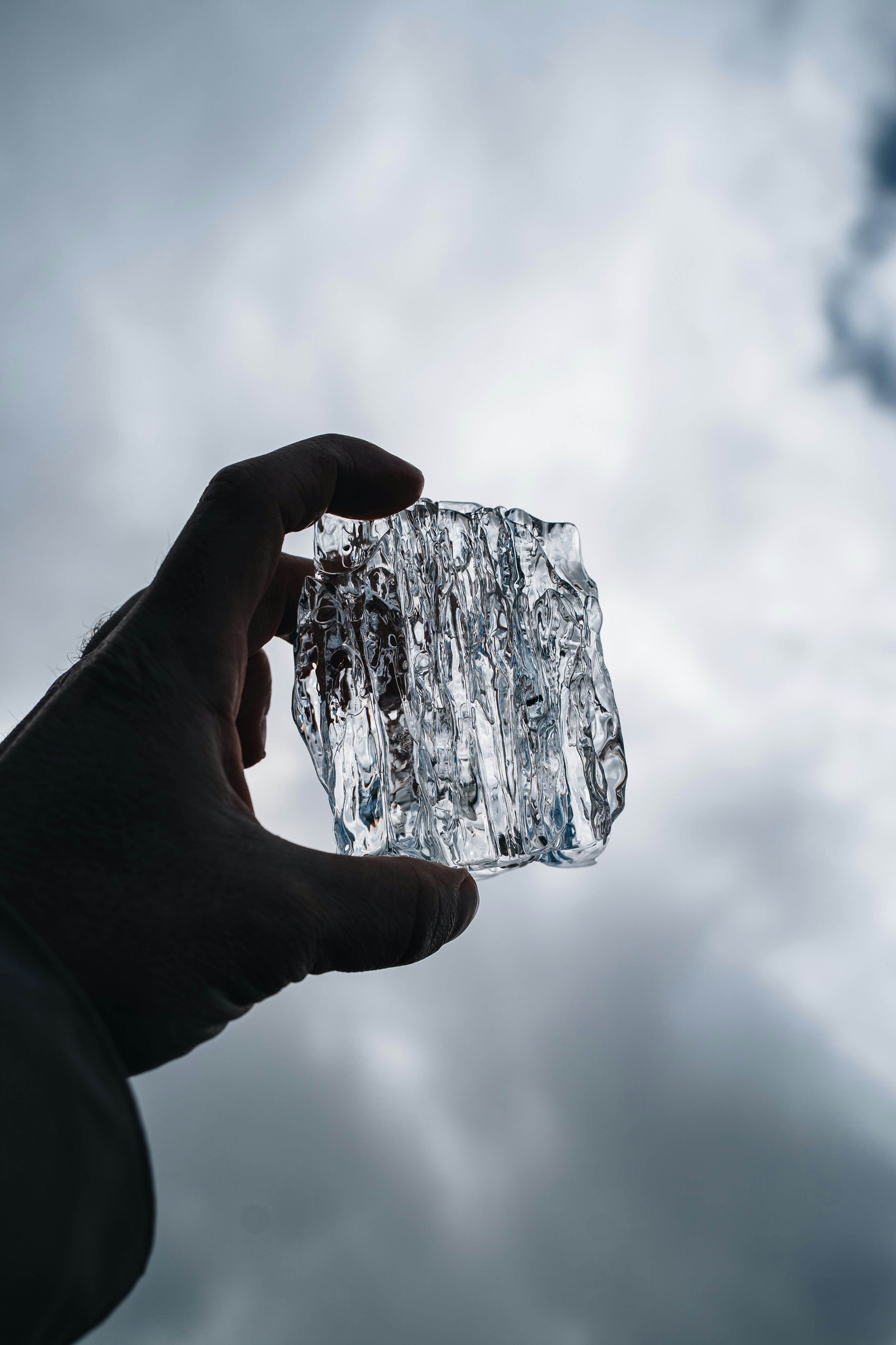 Crystal Crown: A Handheld Ice Fragment Against a Clouded Sky
