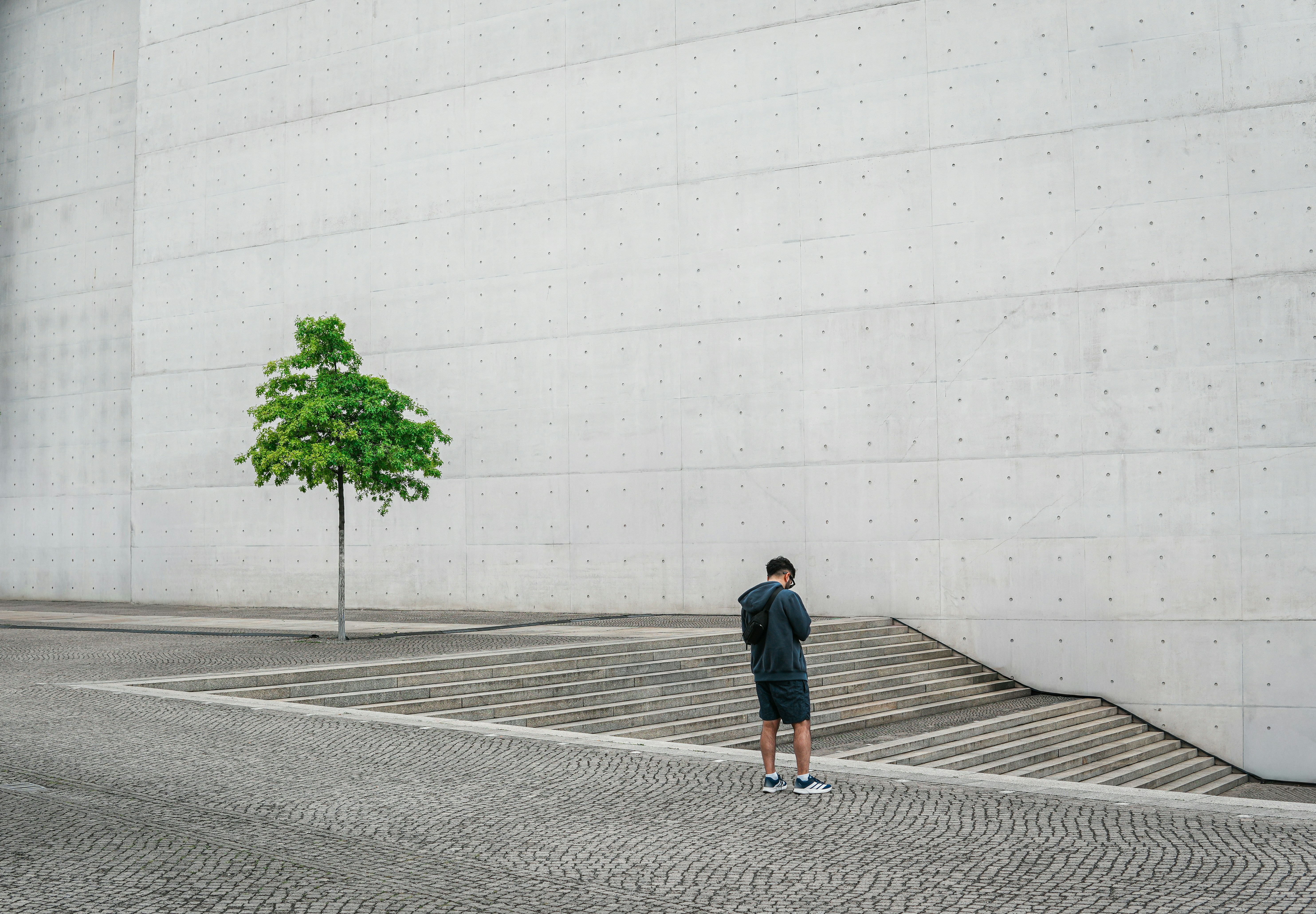  solitary wanderer beside a pale architectural wall