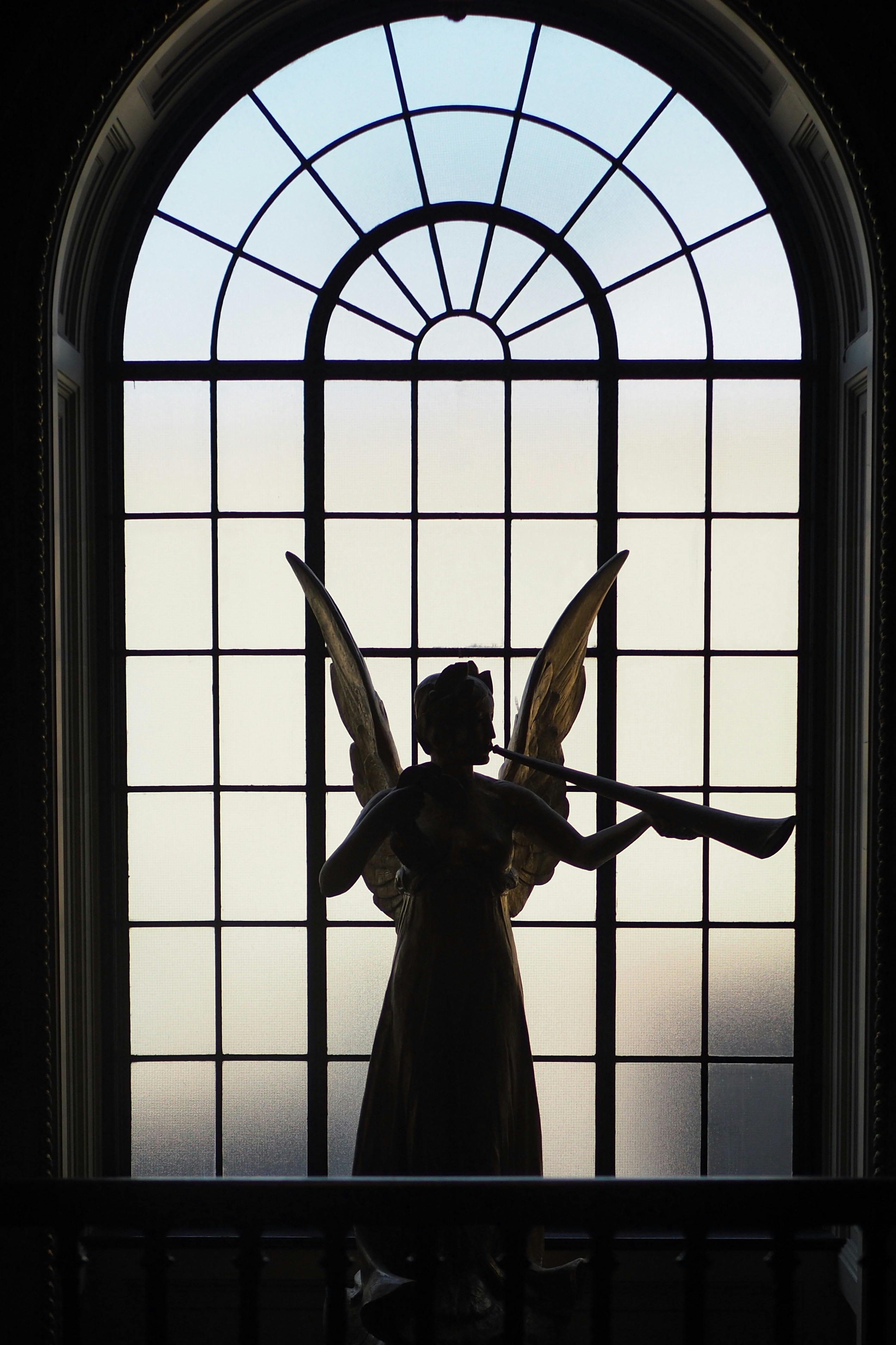 Silhouette of a Winged Figure Stands Before Summit Arch