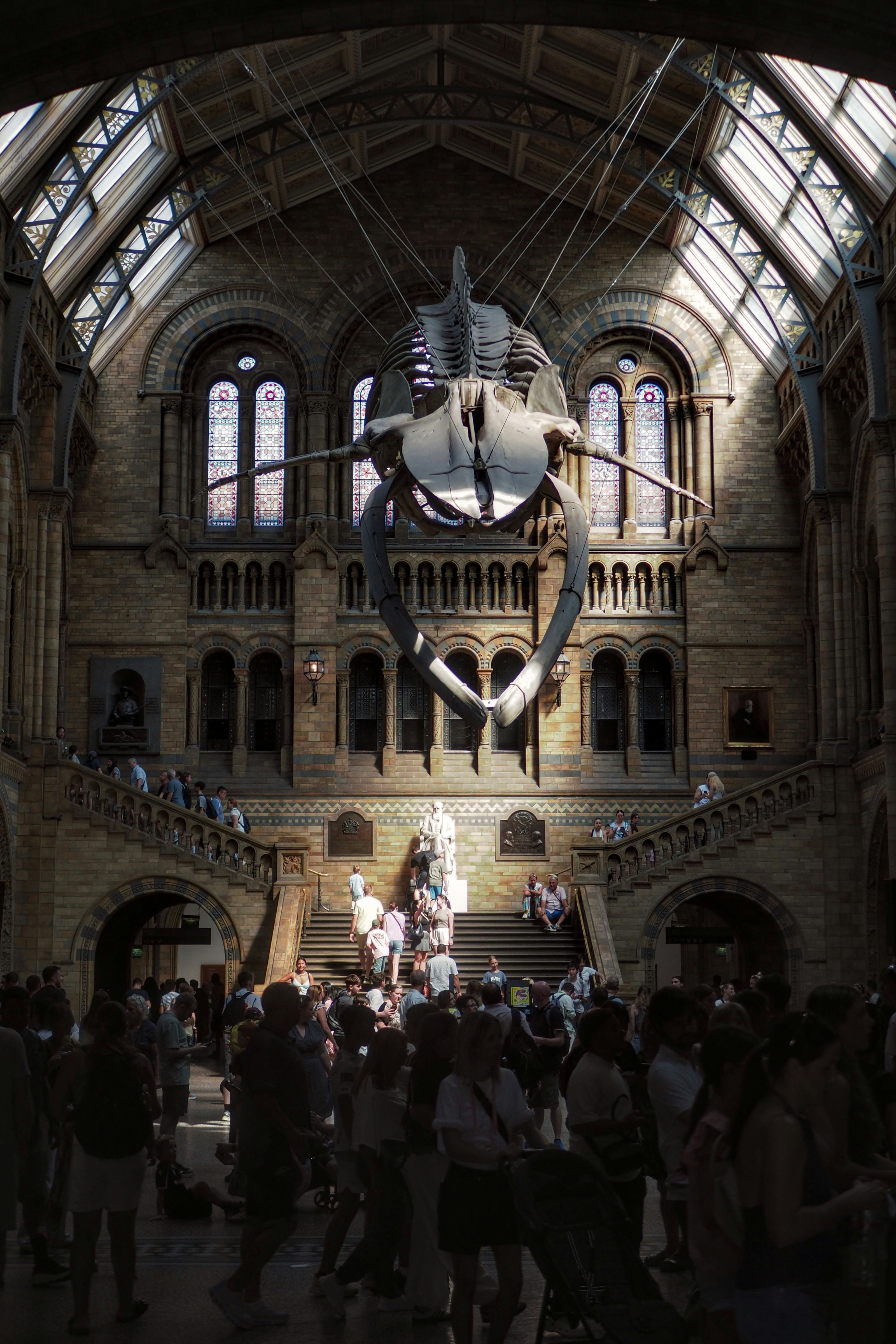 Giant suspended skeleton centerpiece over a museum crowd