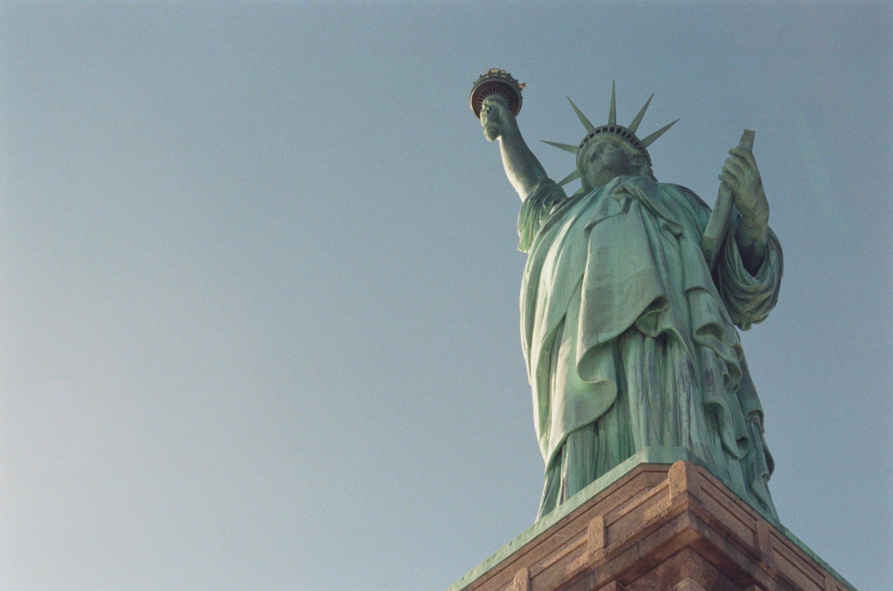 The Statue of Liberty holding a torch against a clear blue sky in New York