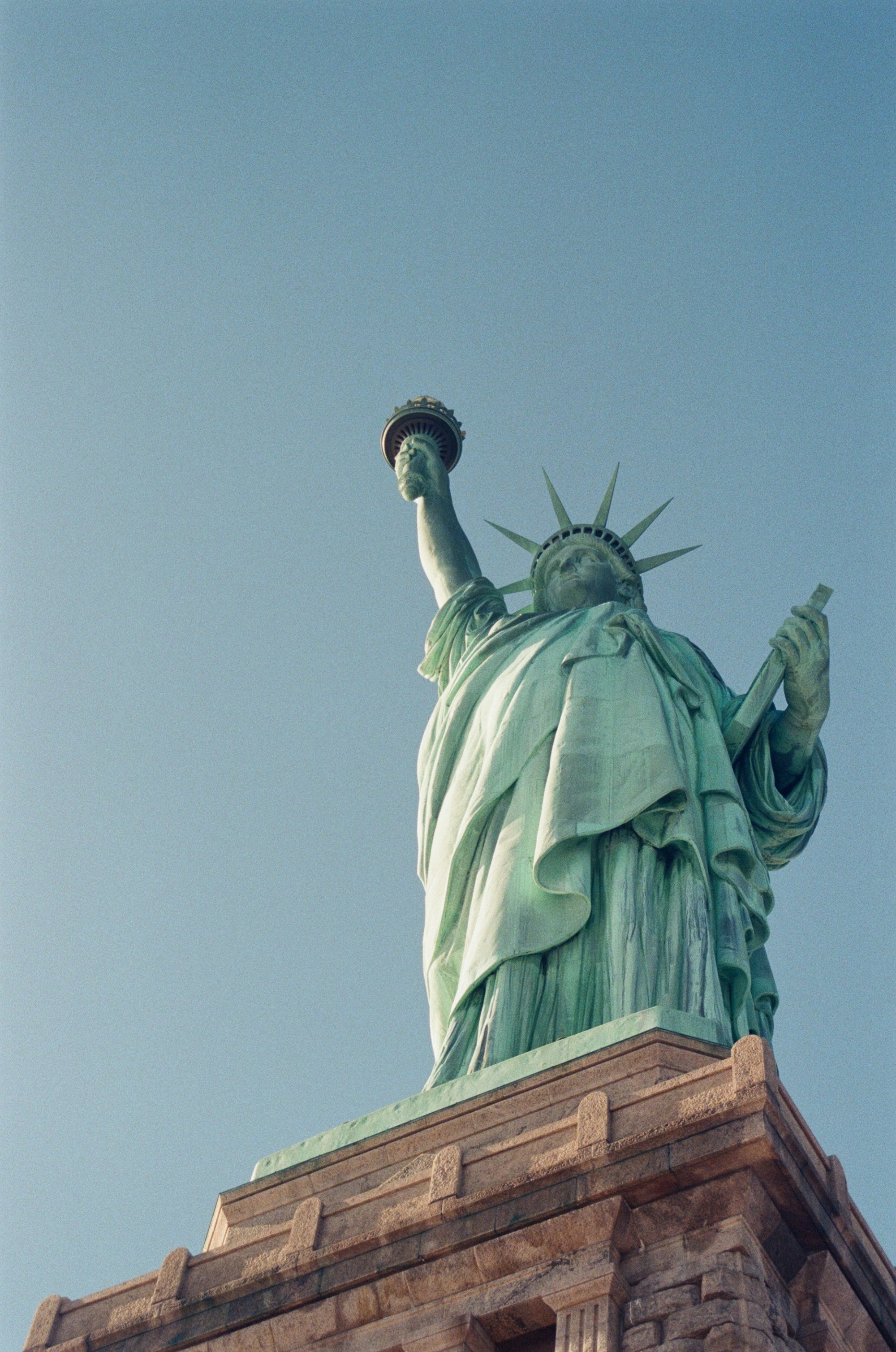 The Statue of Liberty holding a torch against a clear blue sky in New York