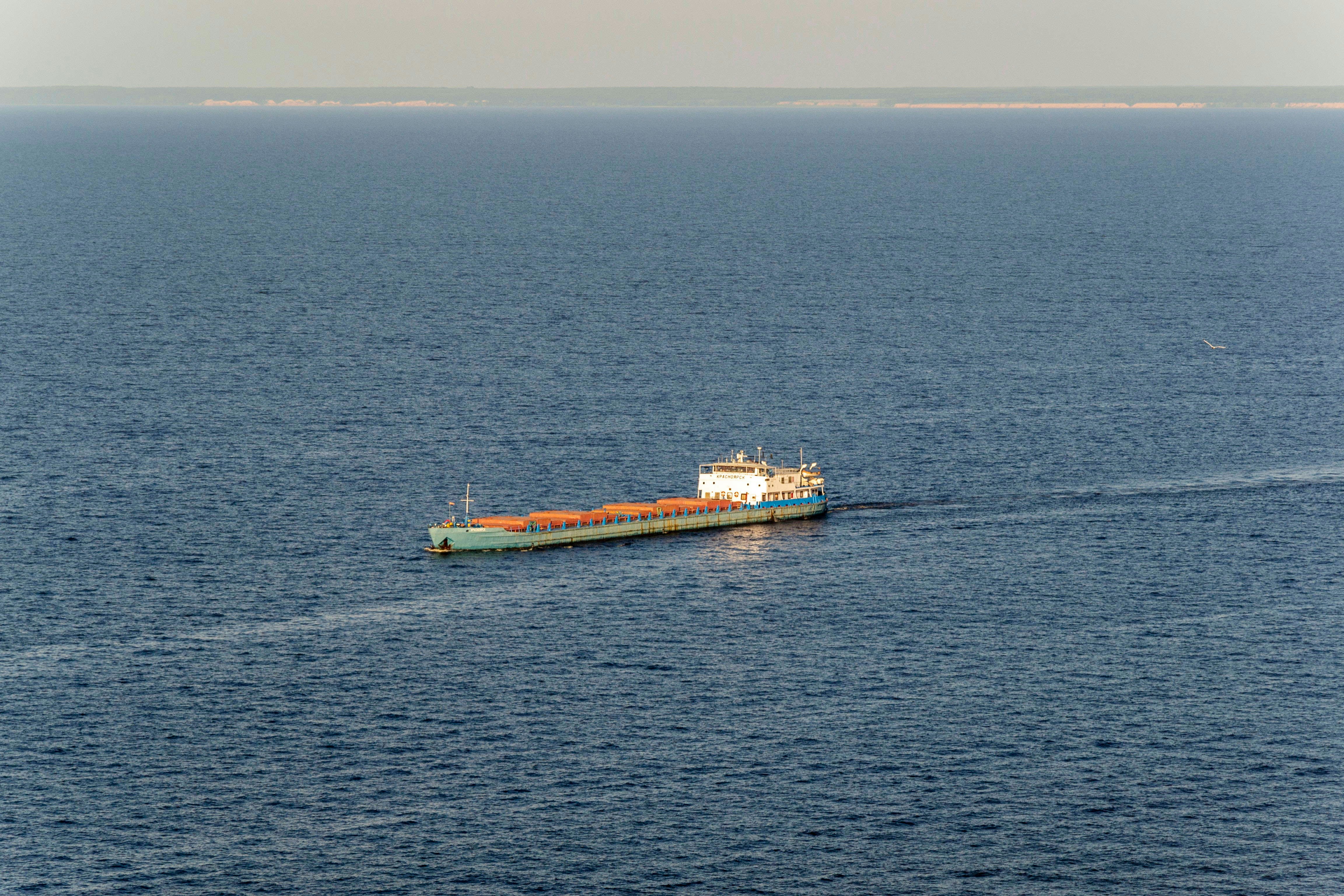 Ocean Freight: A lone cargo barge traces a quiet wake across a vast blue sea