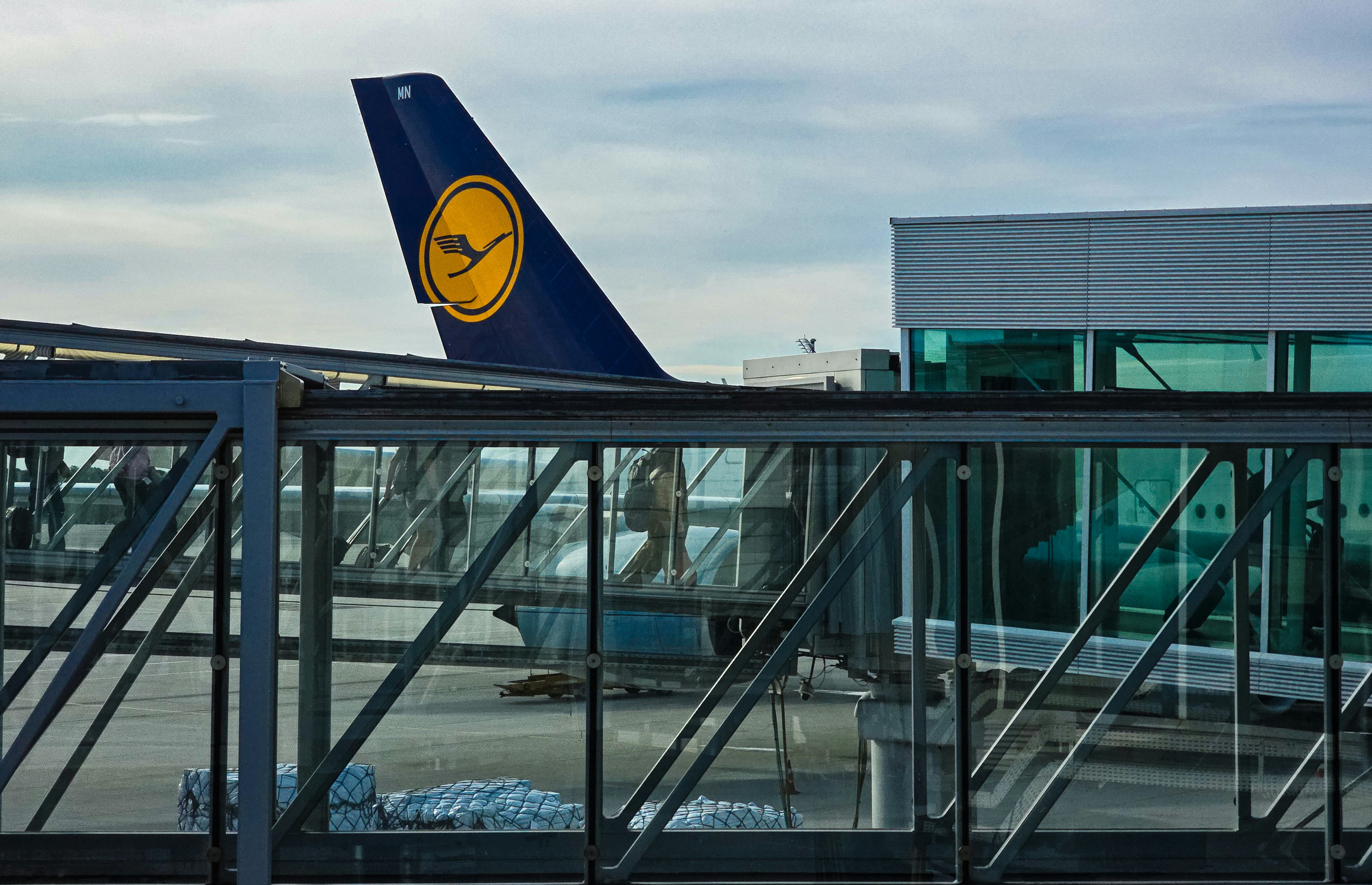 Tailfin at Gate: A Lufthansa silhouette over a glass passage