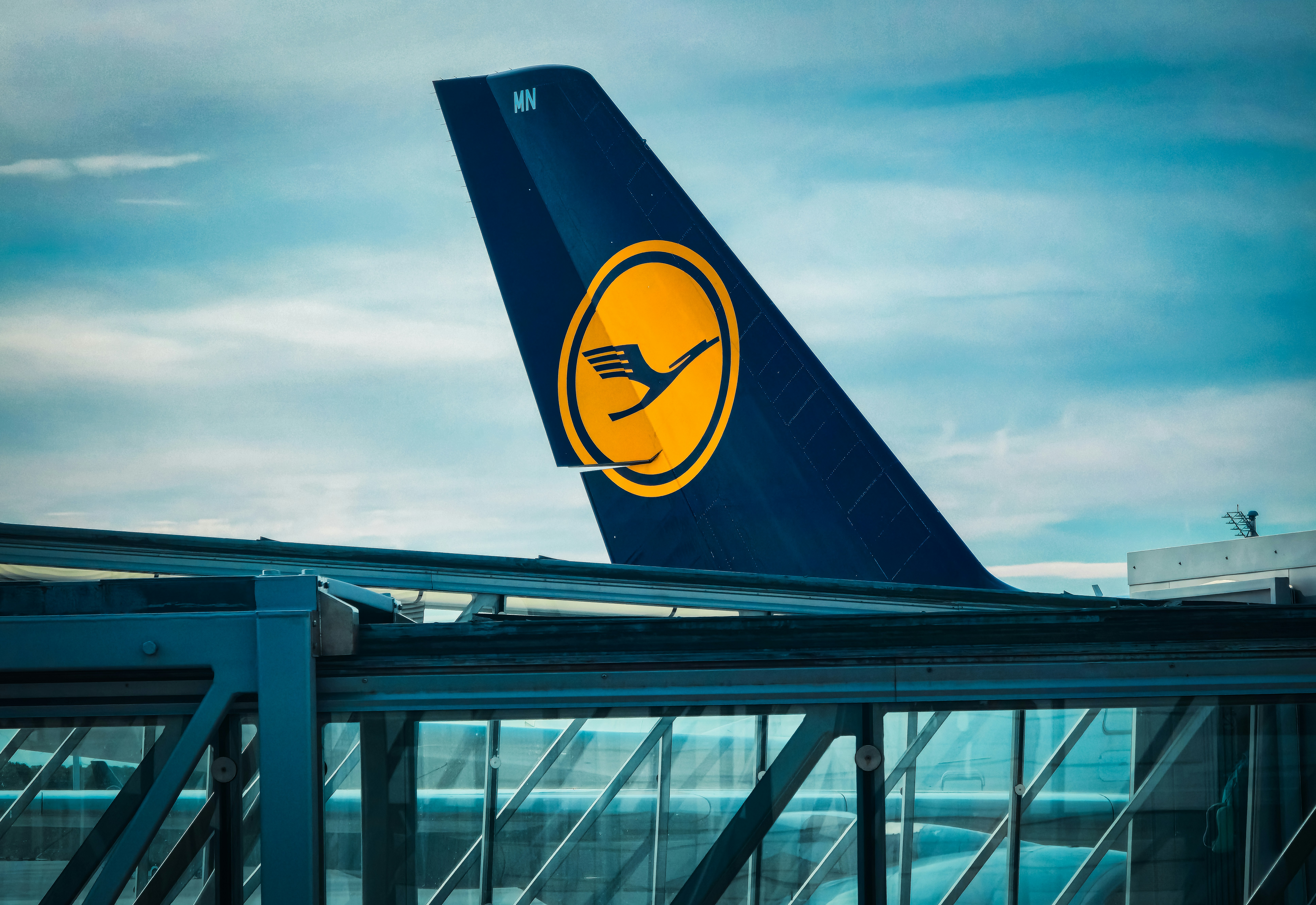 Lufthansa tail silhouette above a glass-bridge at an airport