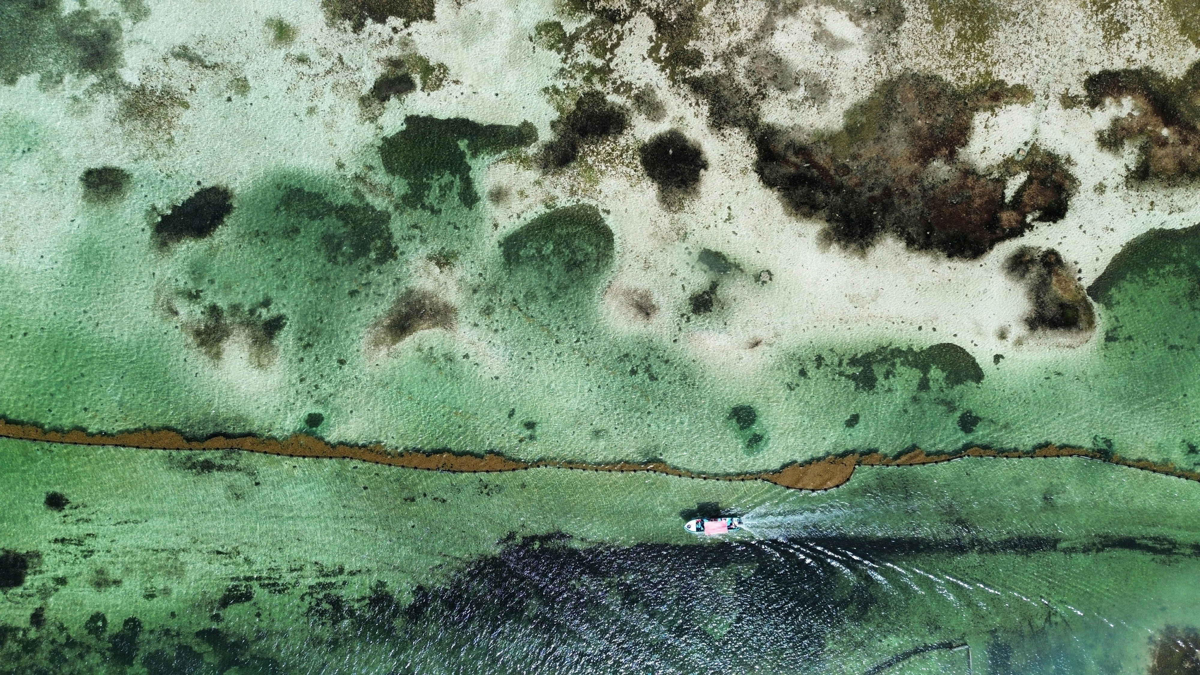 Emerald Shoals: A Tiny Boat Trails a Ribbon of Turquoise