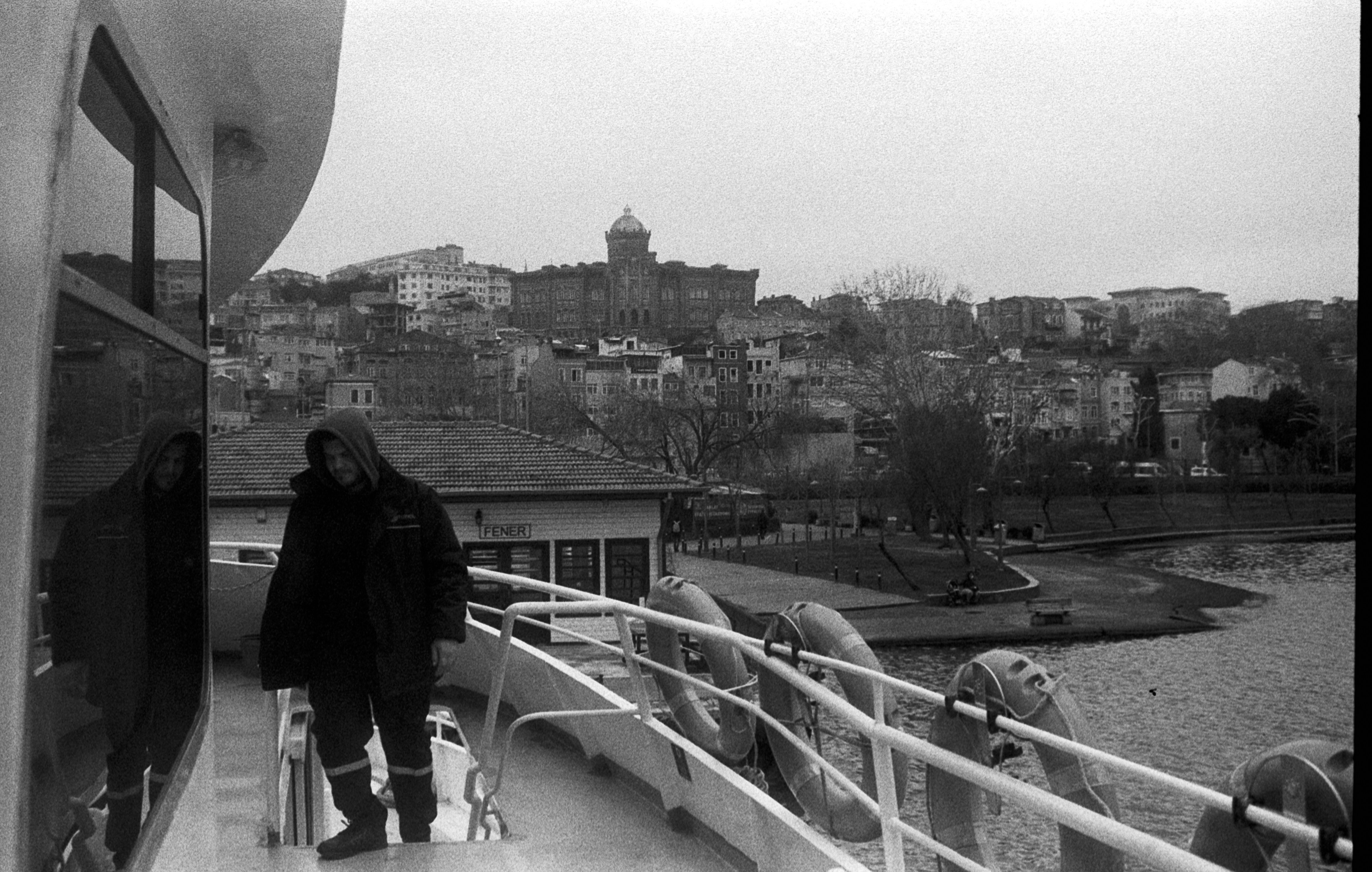Dockside Portrait: Figure on the Deck As the City Gathers in the Background
