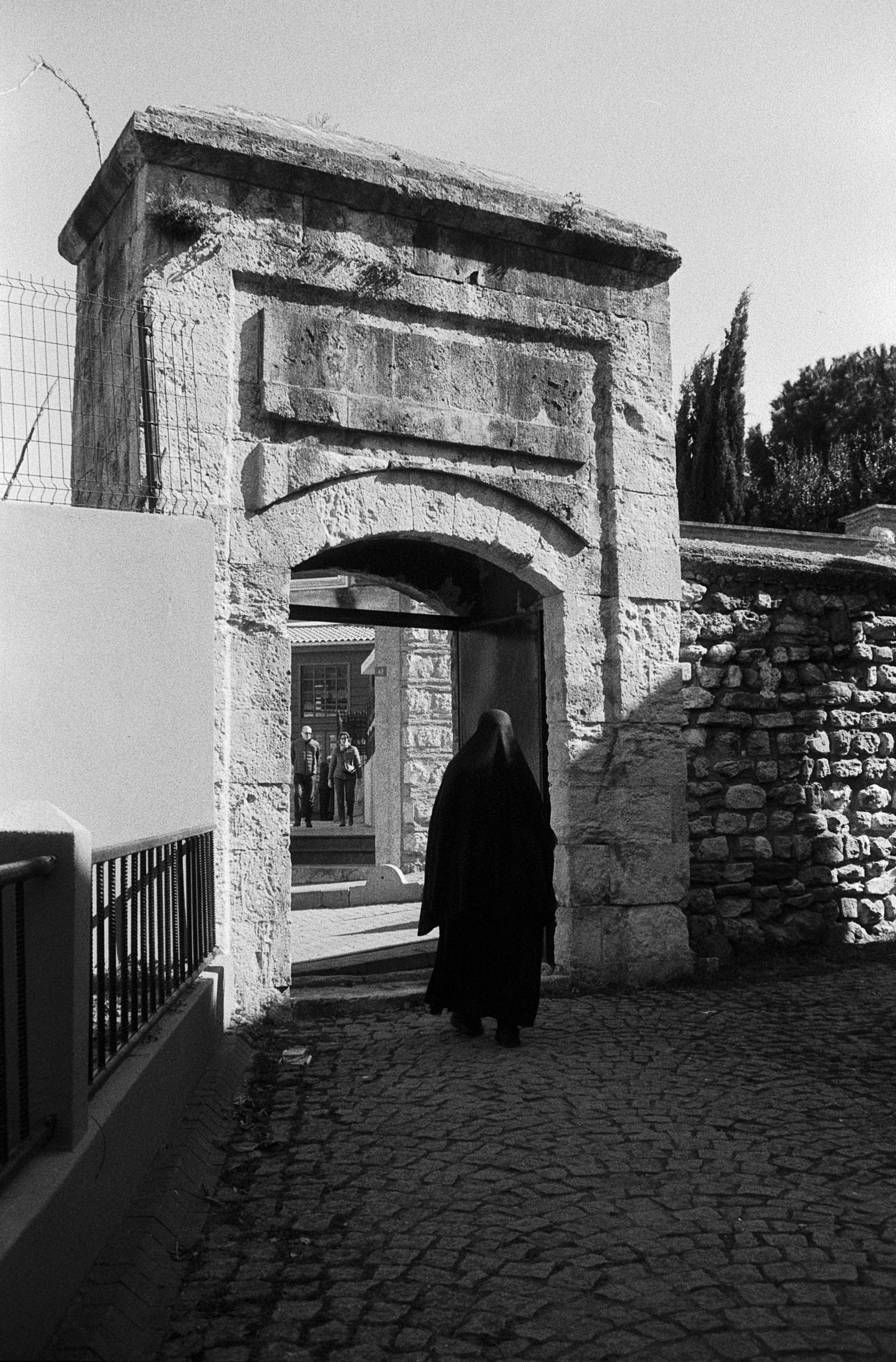 Through the Arch: A Quiet Pilgrim Emerges into the Courtyard