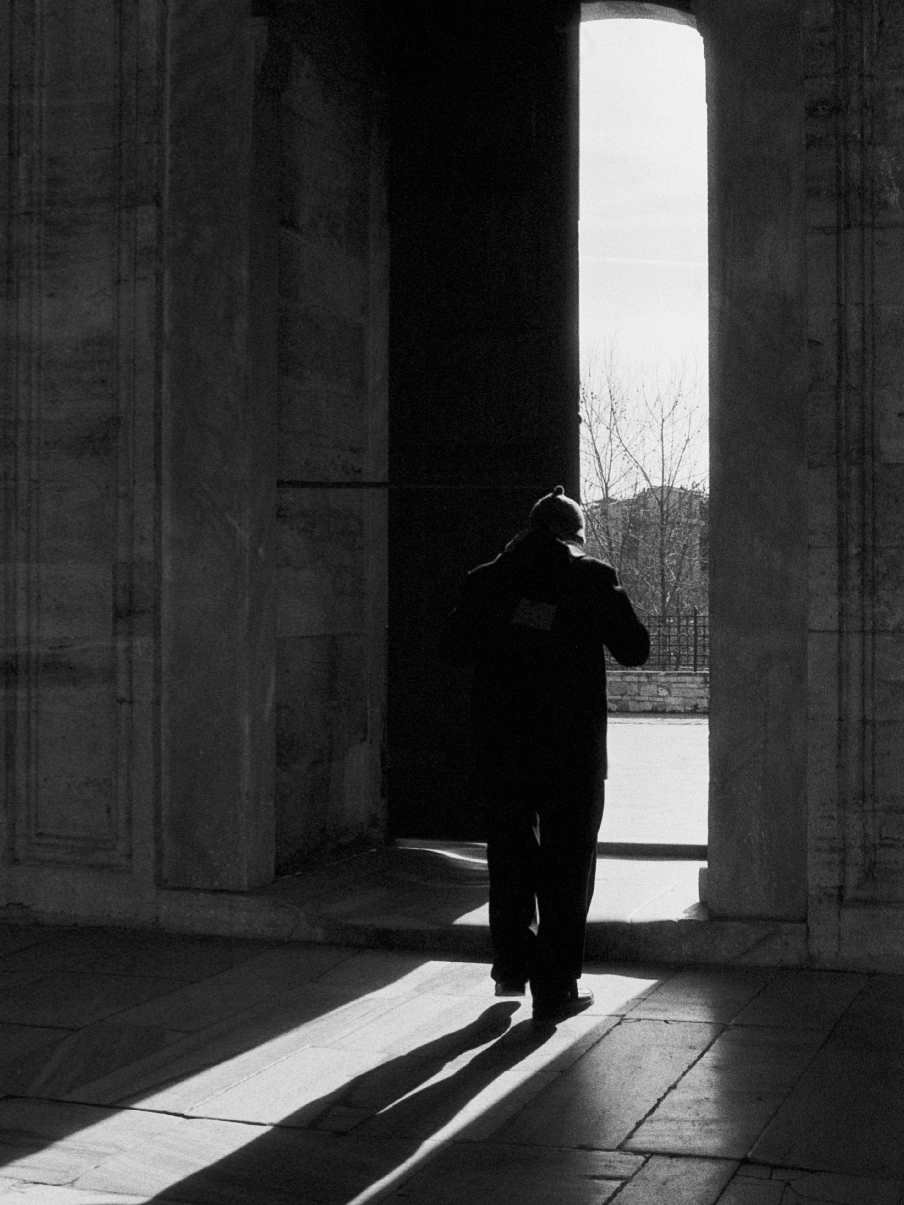 Shadowed Passage: A lone figure framed by a bright doorway