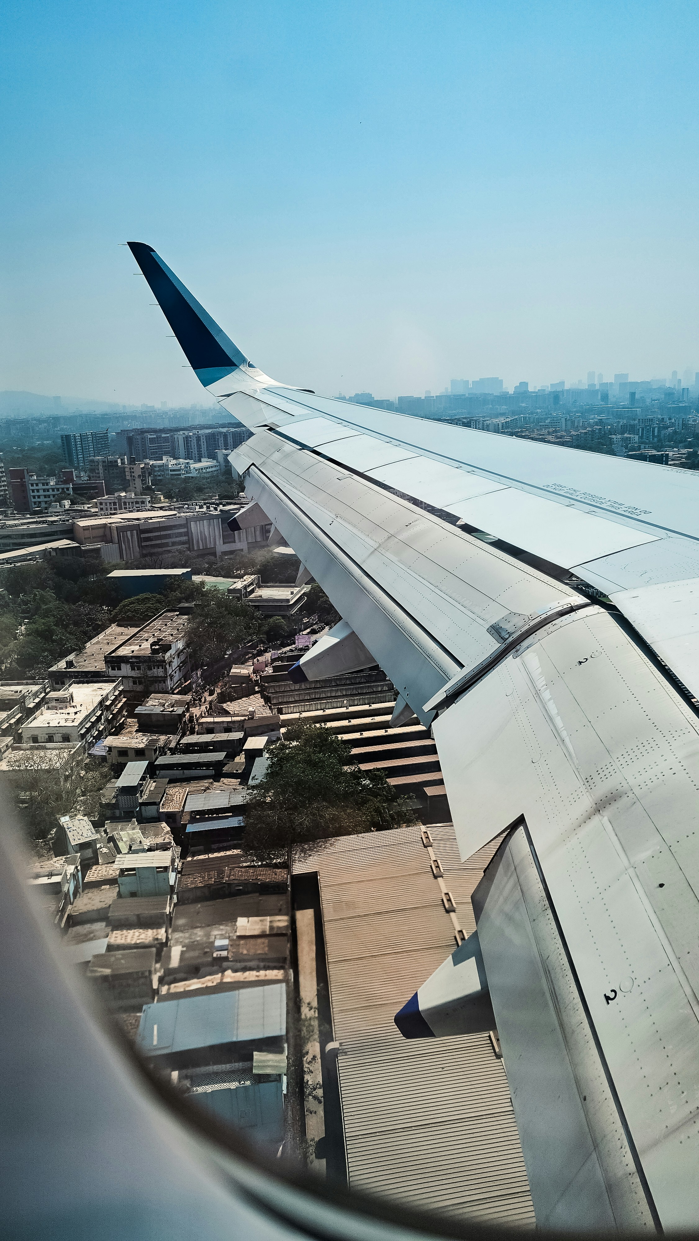 Wings Over a Concrete Cityscape: A Window View from the Jet