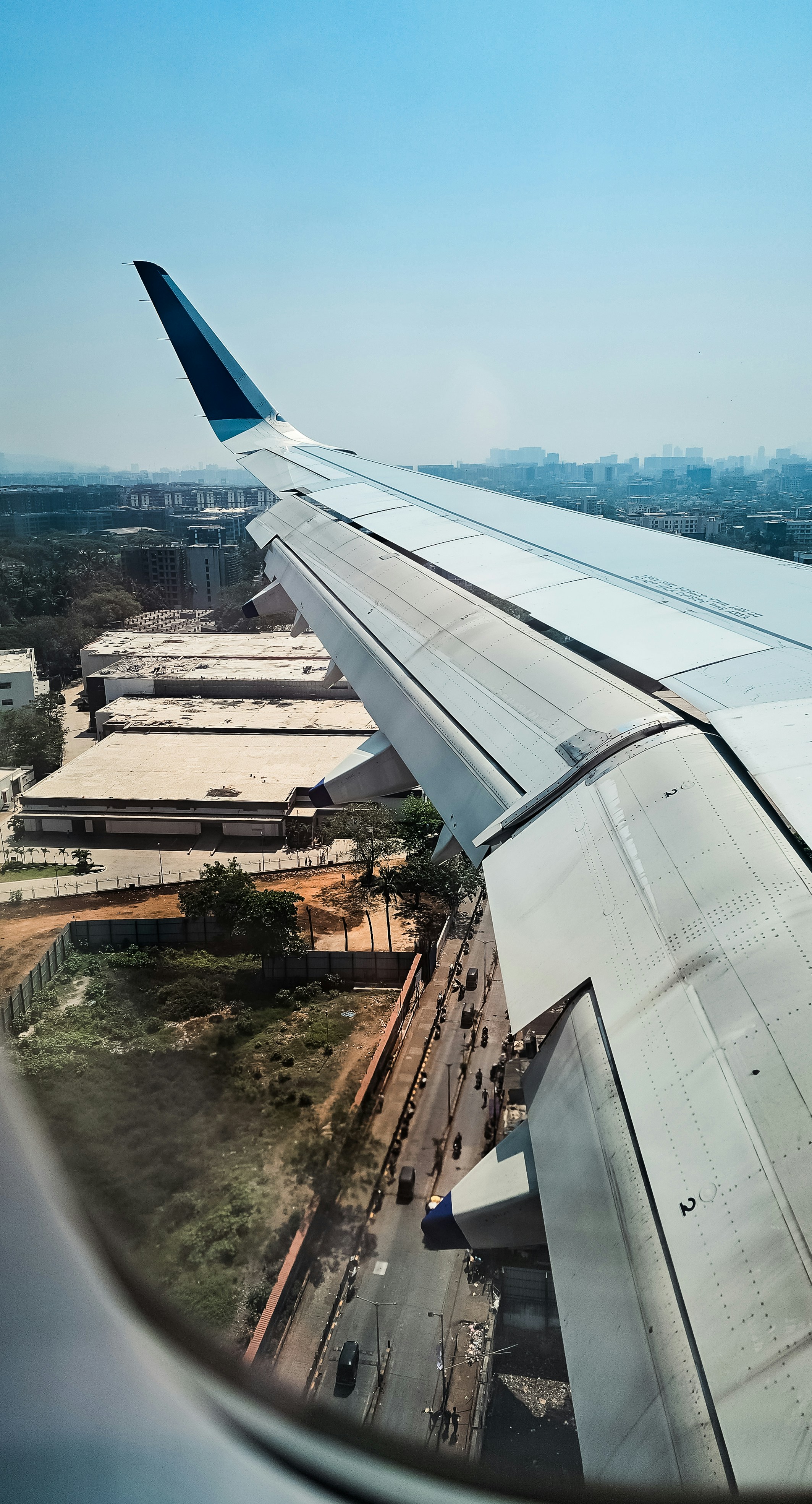 Aerial view from my aircraft window during landing at Chhatrapati Shivaji Maharaj International Airport in Mumbai, India, with the aircraft wing visible above Mumbai's densely developed urban landscape.