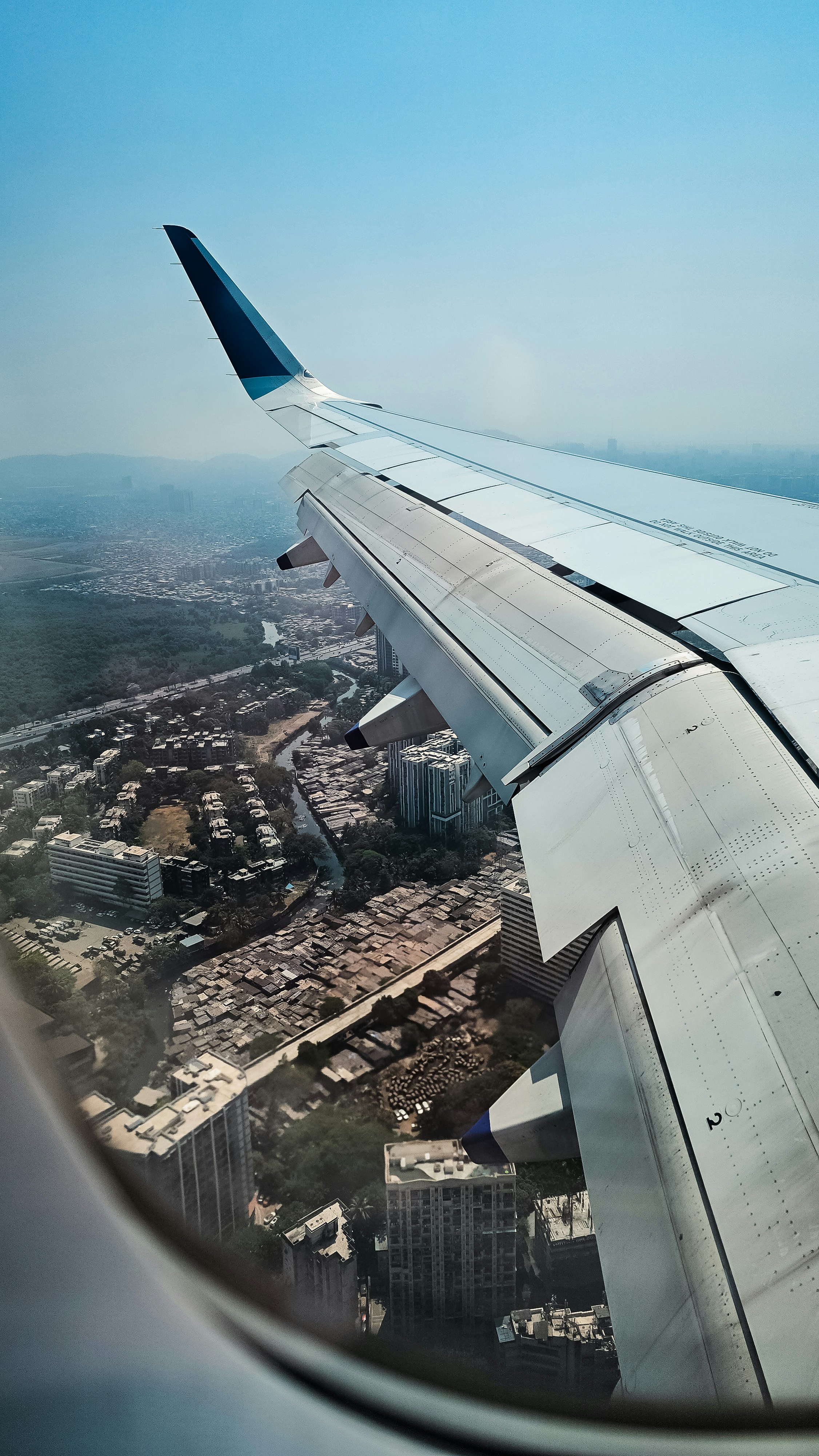 Aerial view from my aircraft window during landing at Chhatrapati Shivaji Maharaj International Airport in Mumbai, India, with the aircraft wing visible above Mumbai's densely developed urban landscape.