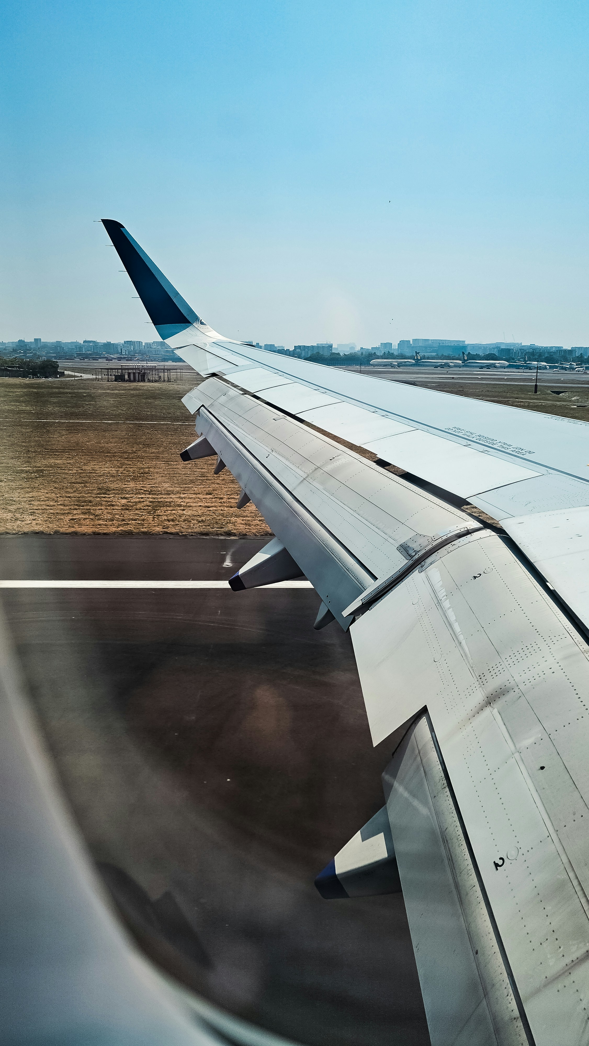 Wing in Focus: A Flight Over Tarmac and Horizon