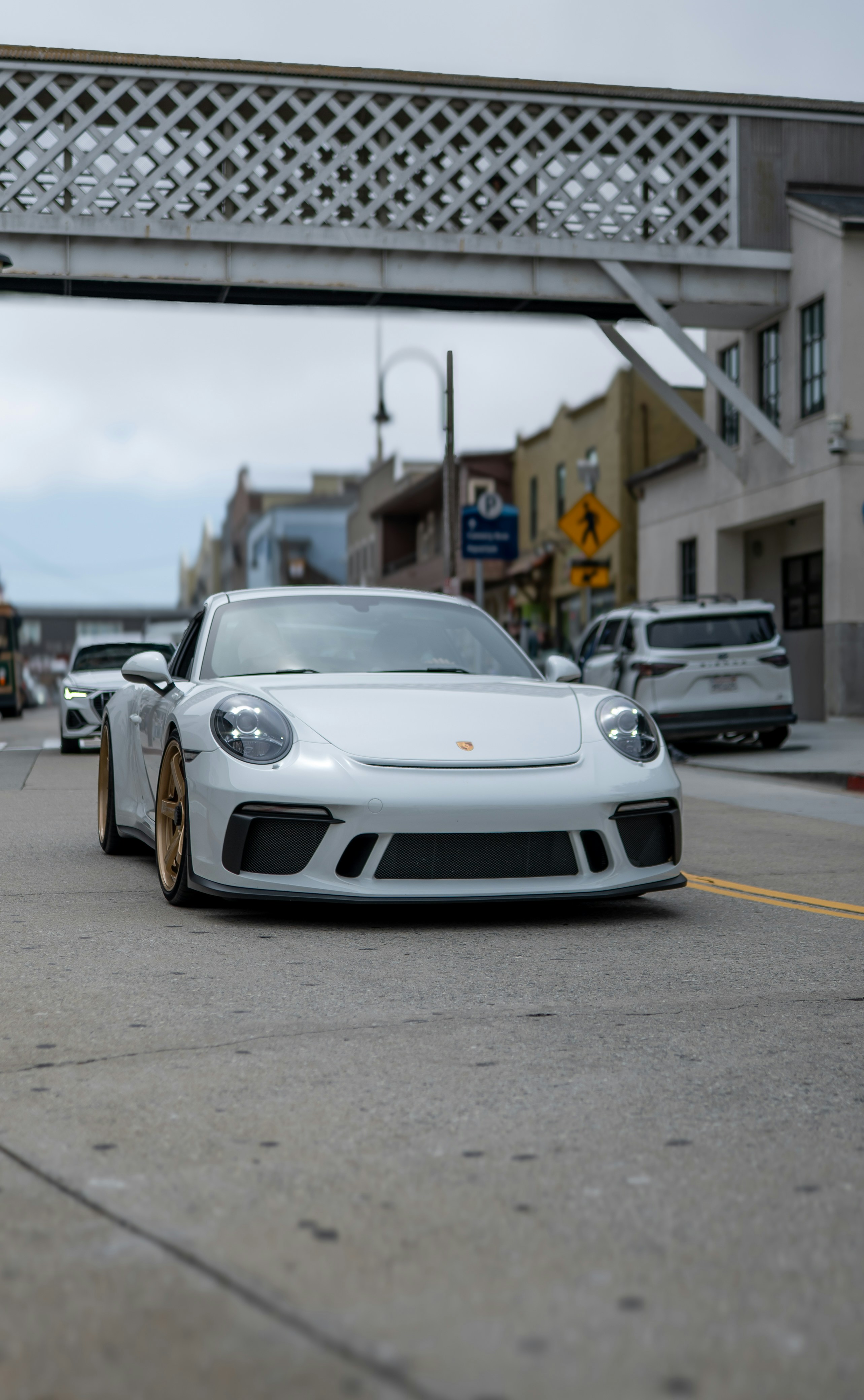 White Porsche leads the street as urban backdrop blurs with depth