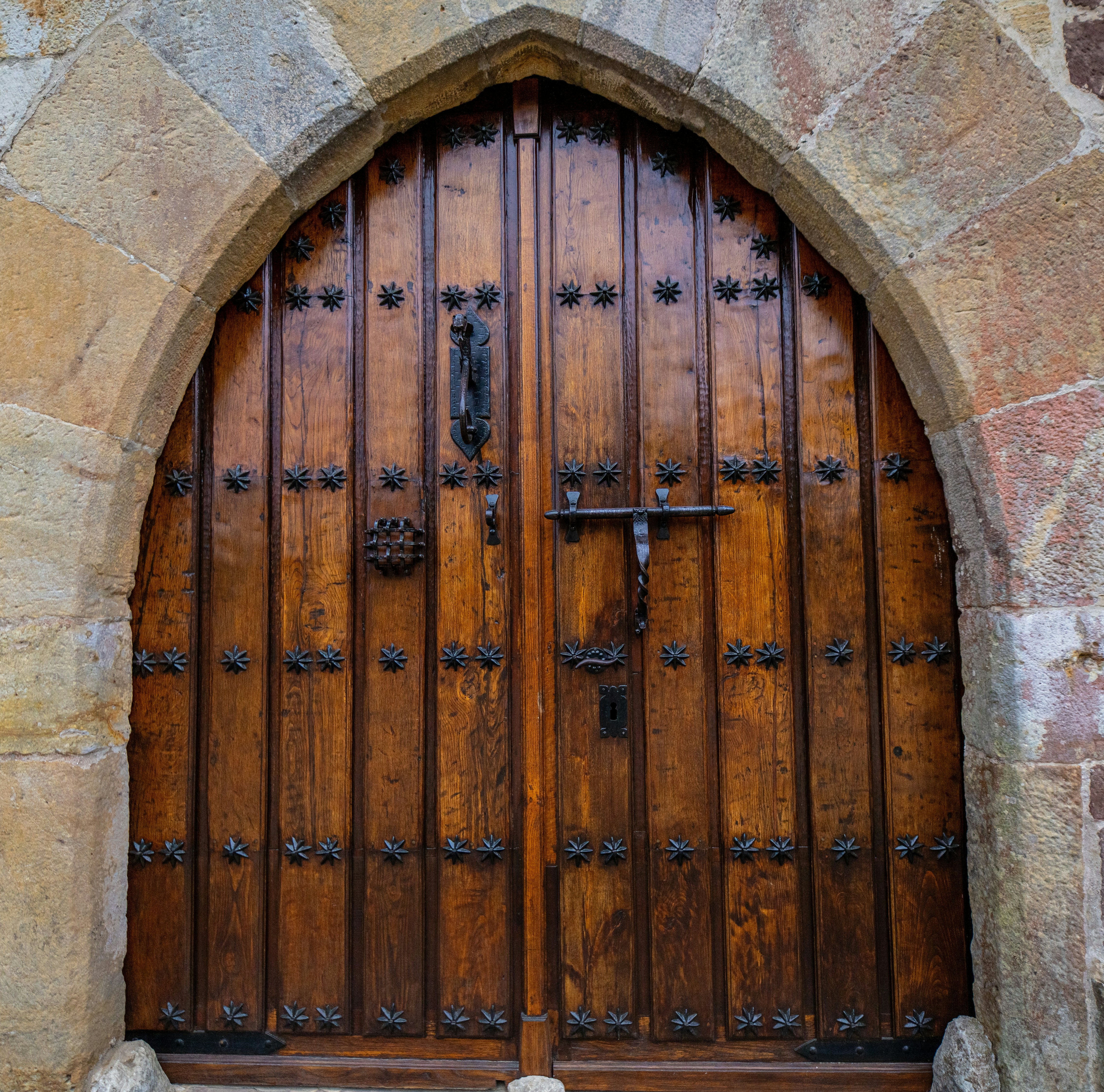 An arched wooden door with iron studs set in a stone wall
