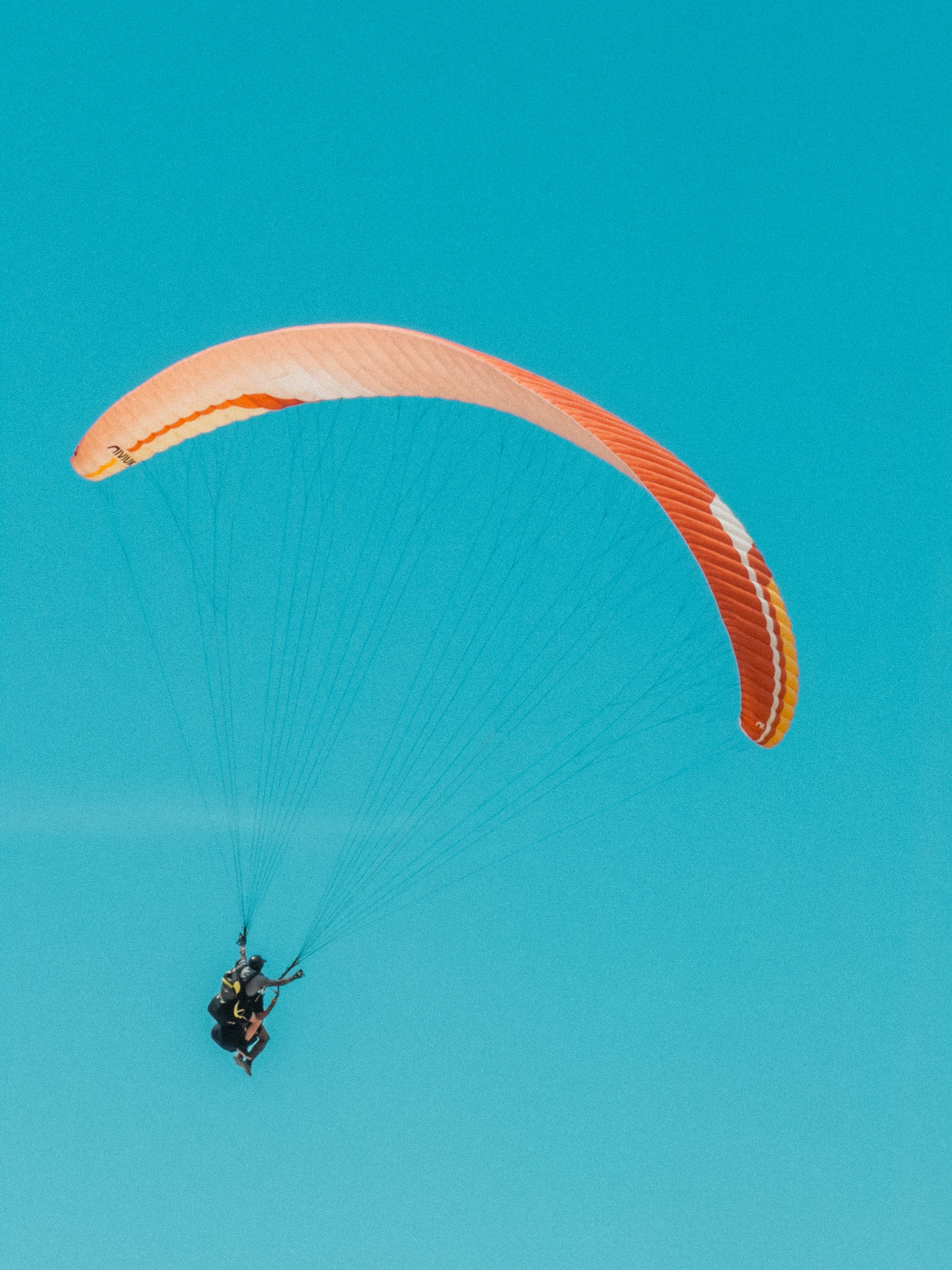 Orange sail gliding across a vivid blue sky