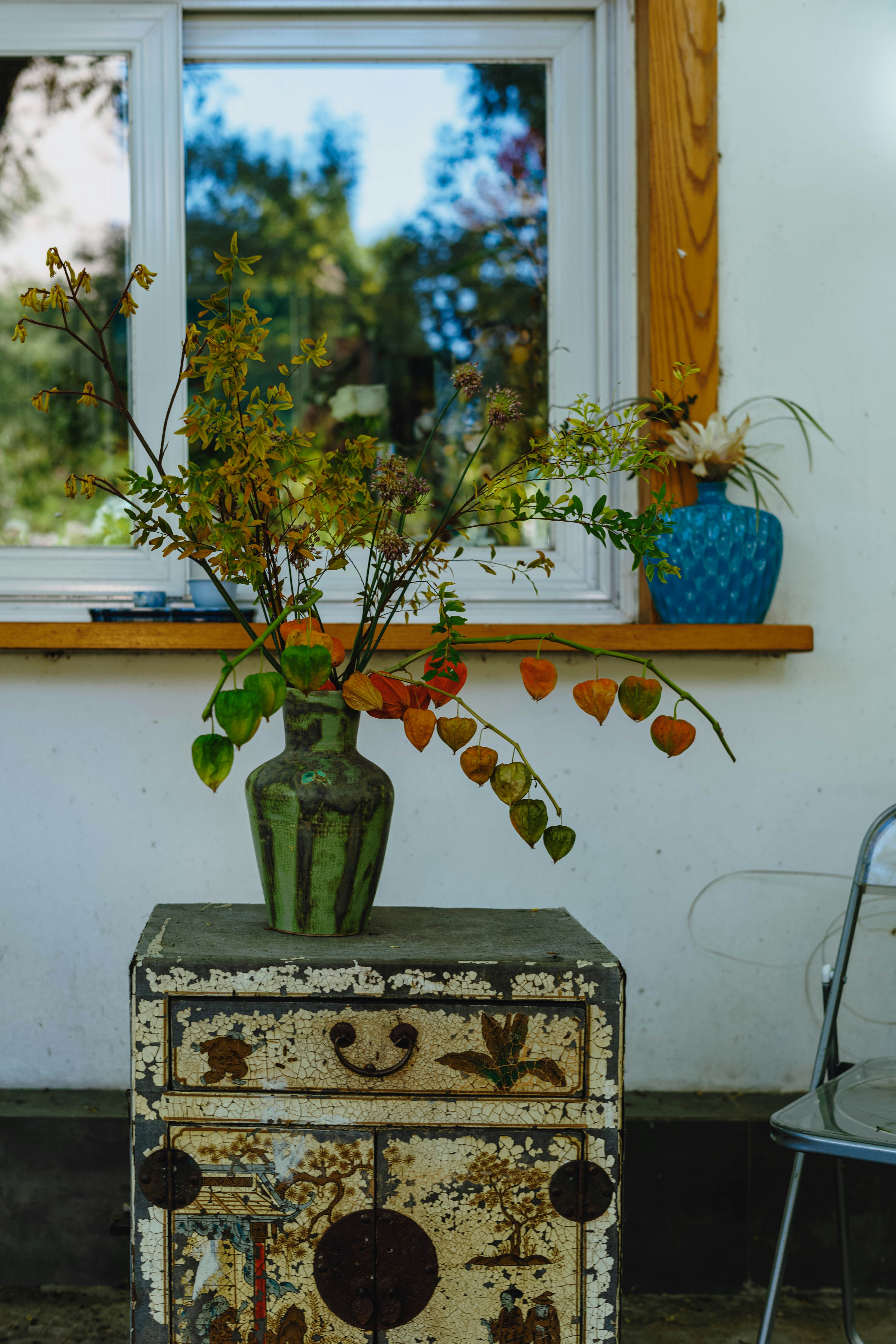 Still Life with Vines: A Rustic Vase on a Story-Worn Chest