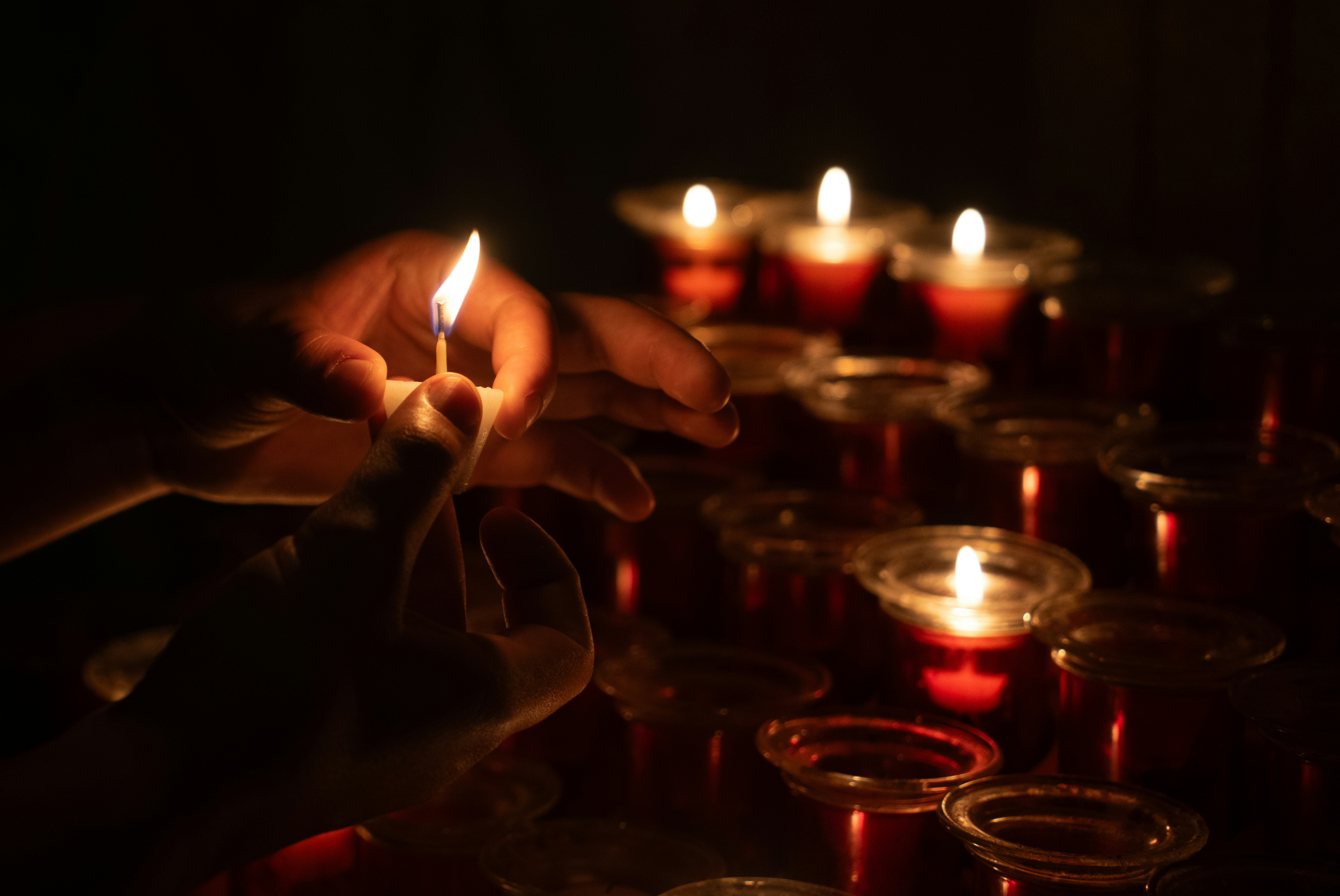 Sparks of Focus: Hand Lighting a Row of Candles in Low Light