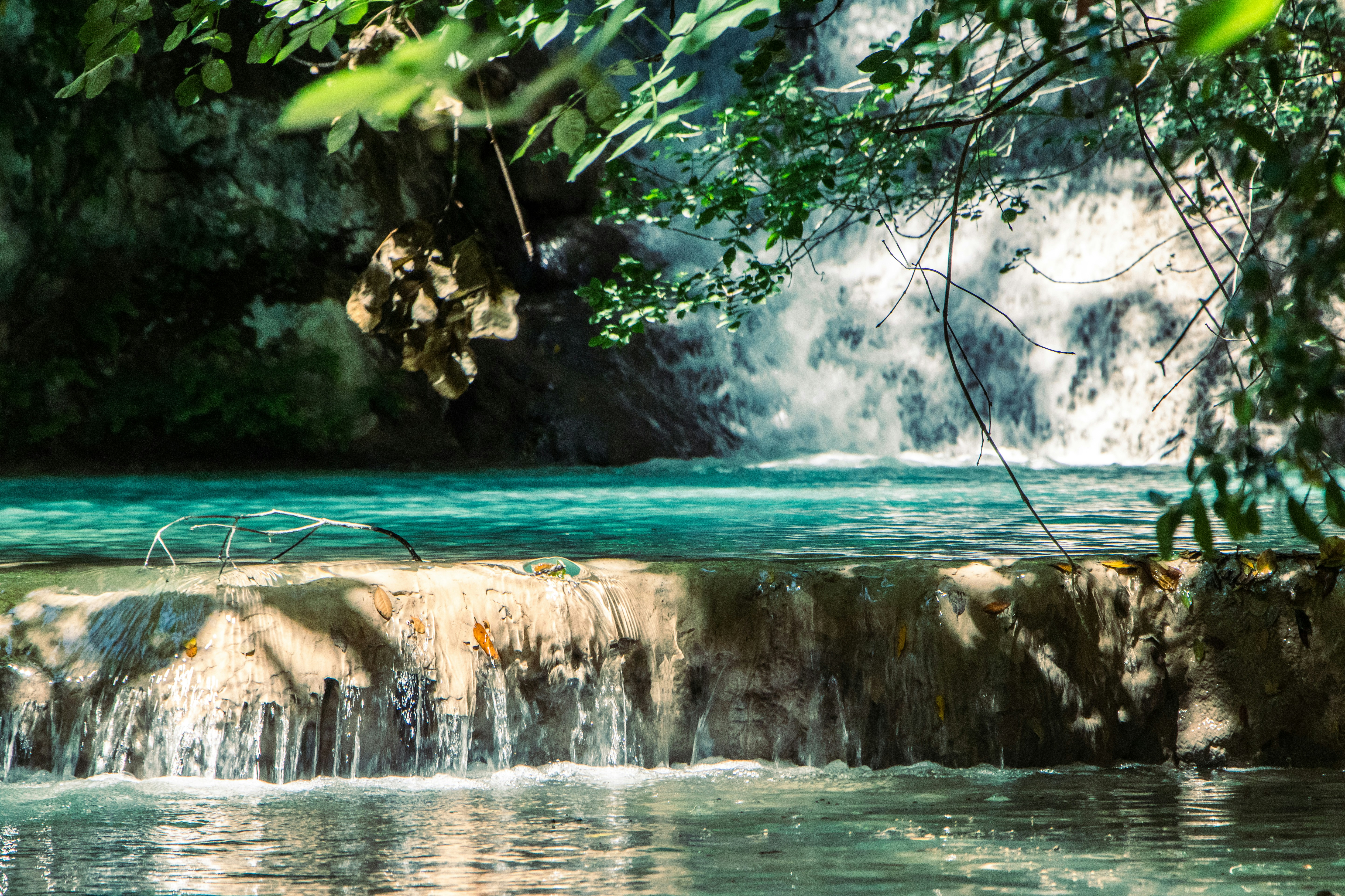 Hidden cascade over turquoise pools framed by emerald canopy