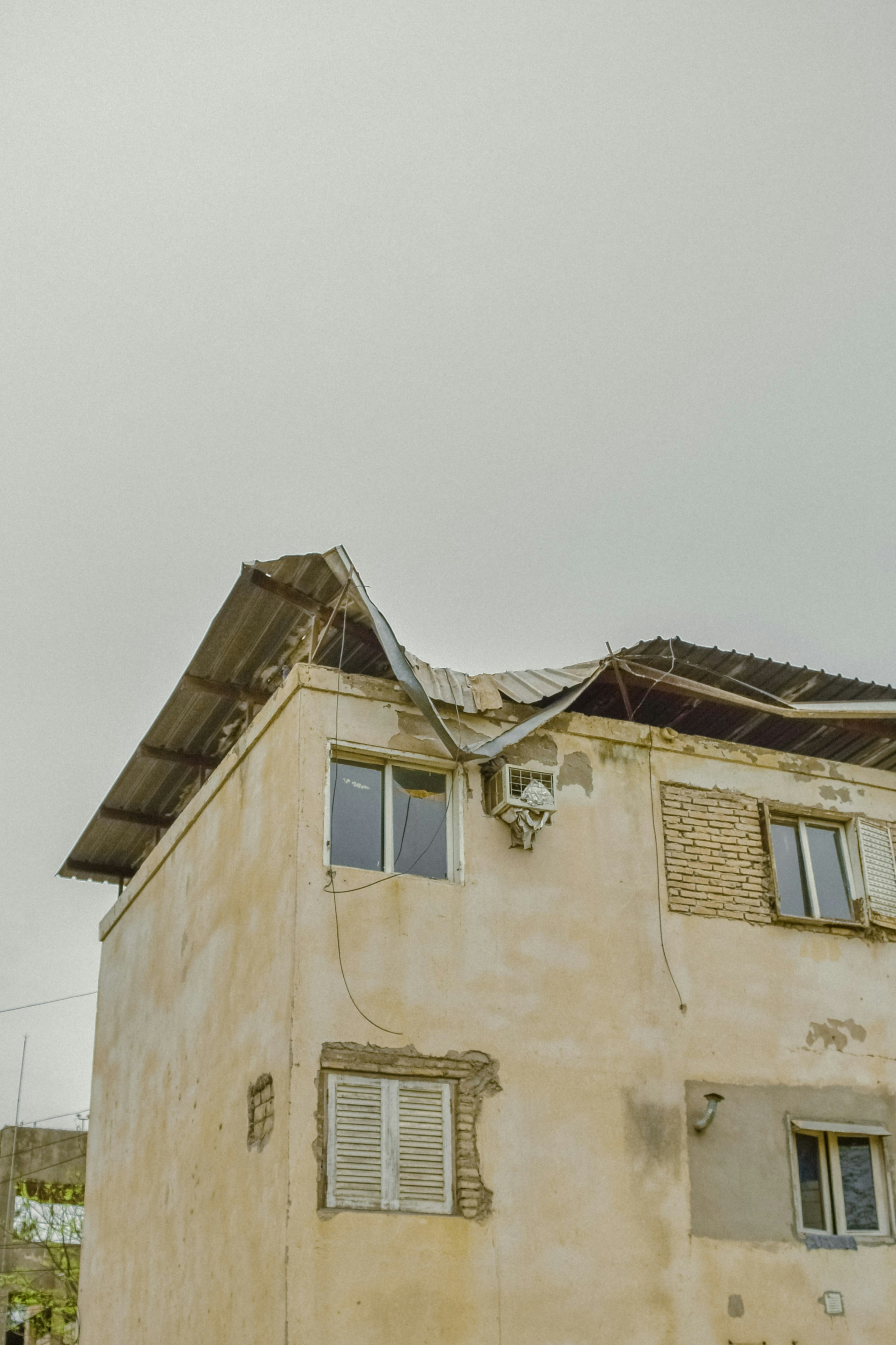 Dilapidated rooftop and weathered masonry under pale sky