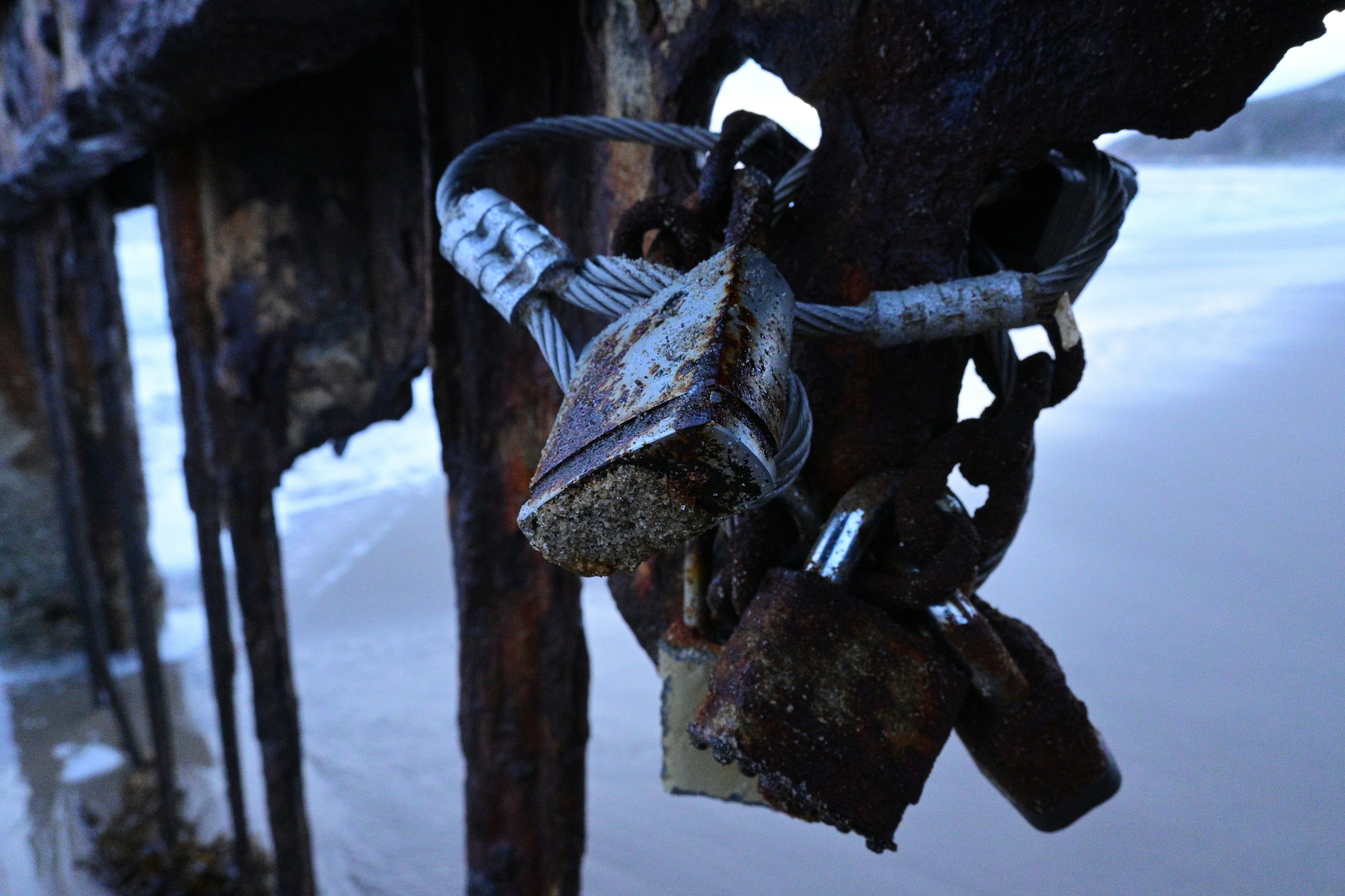 Weathered Locks: A Close-Up on Rusted Ties Under an Icy Pier