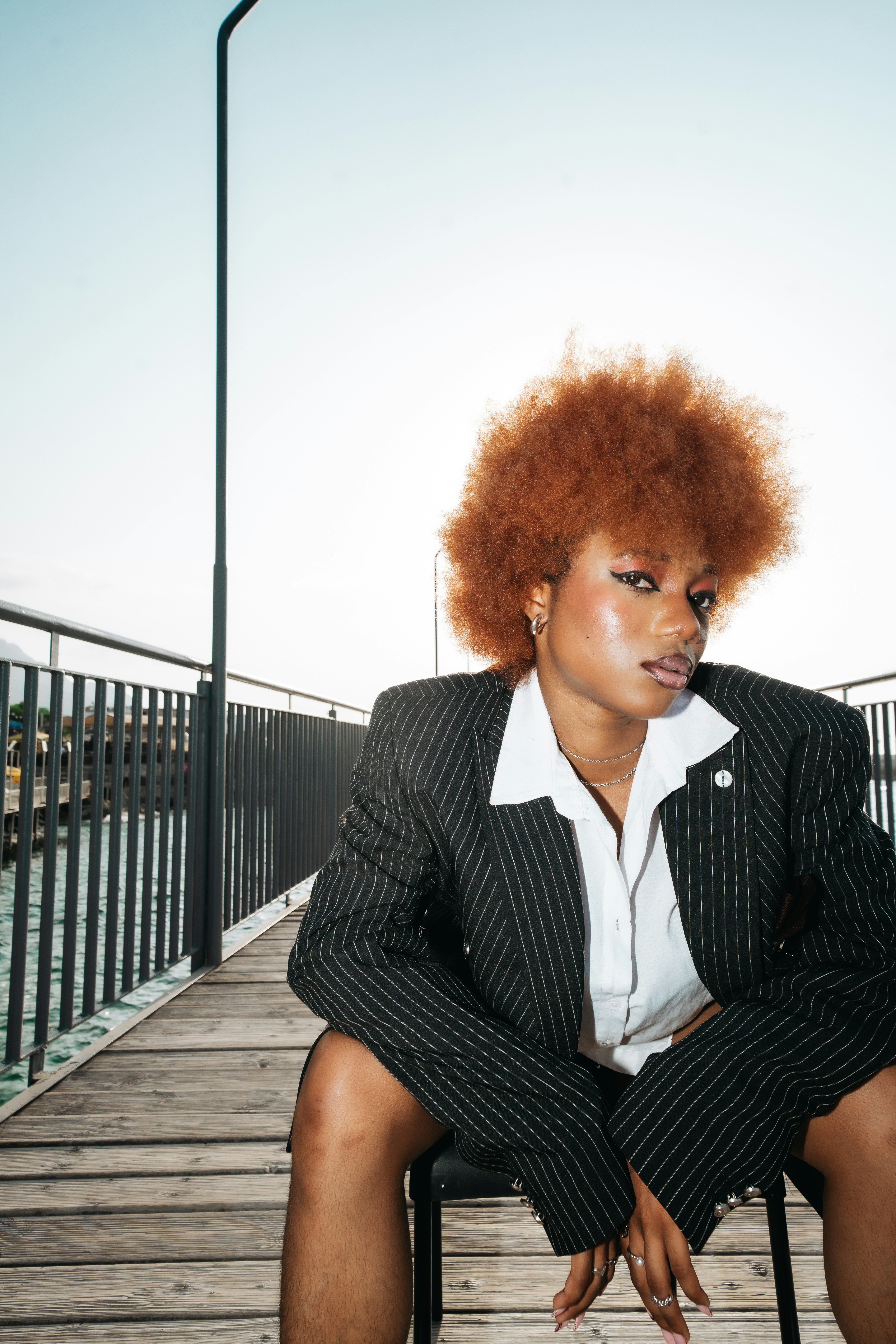 Power Pose on the Pier: Pinstripe Suit, Copper Curls, and City Light