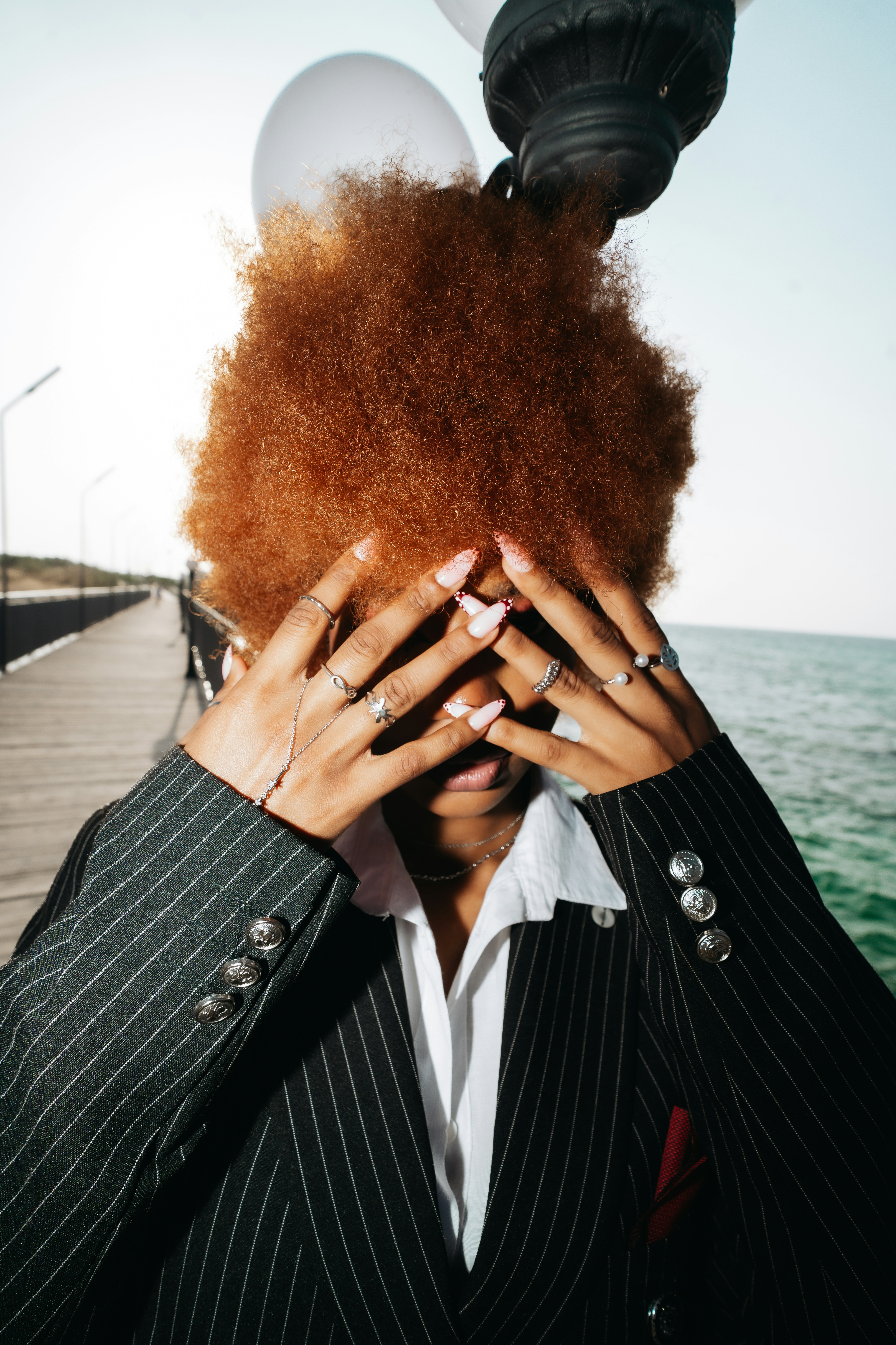 Afro Fashion on the Pier: Hands in Focus Shrouding the Face