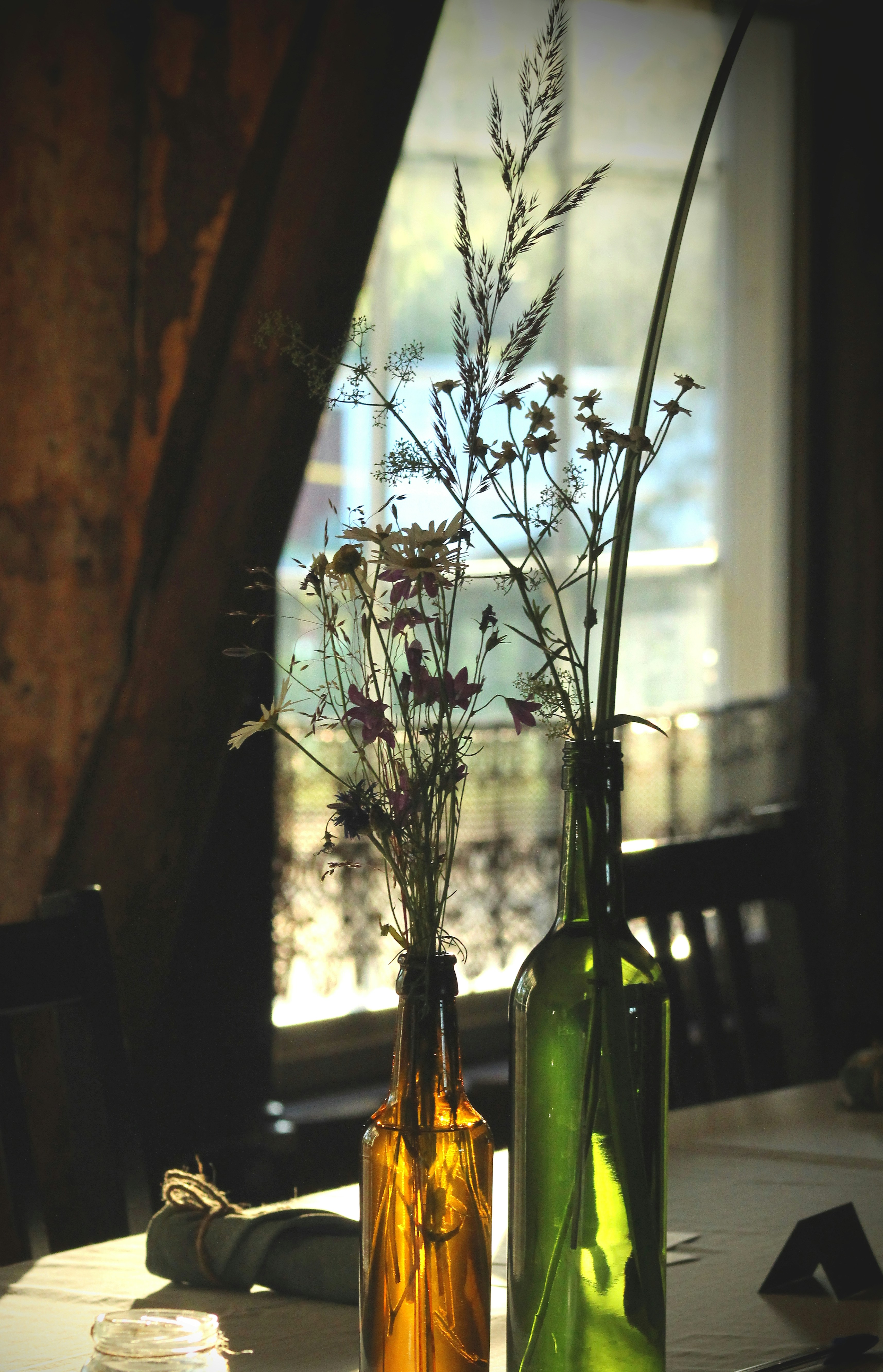 Blooming still life: glass bottles and wildflowers at soft windowlight