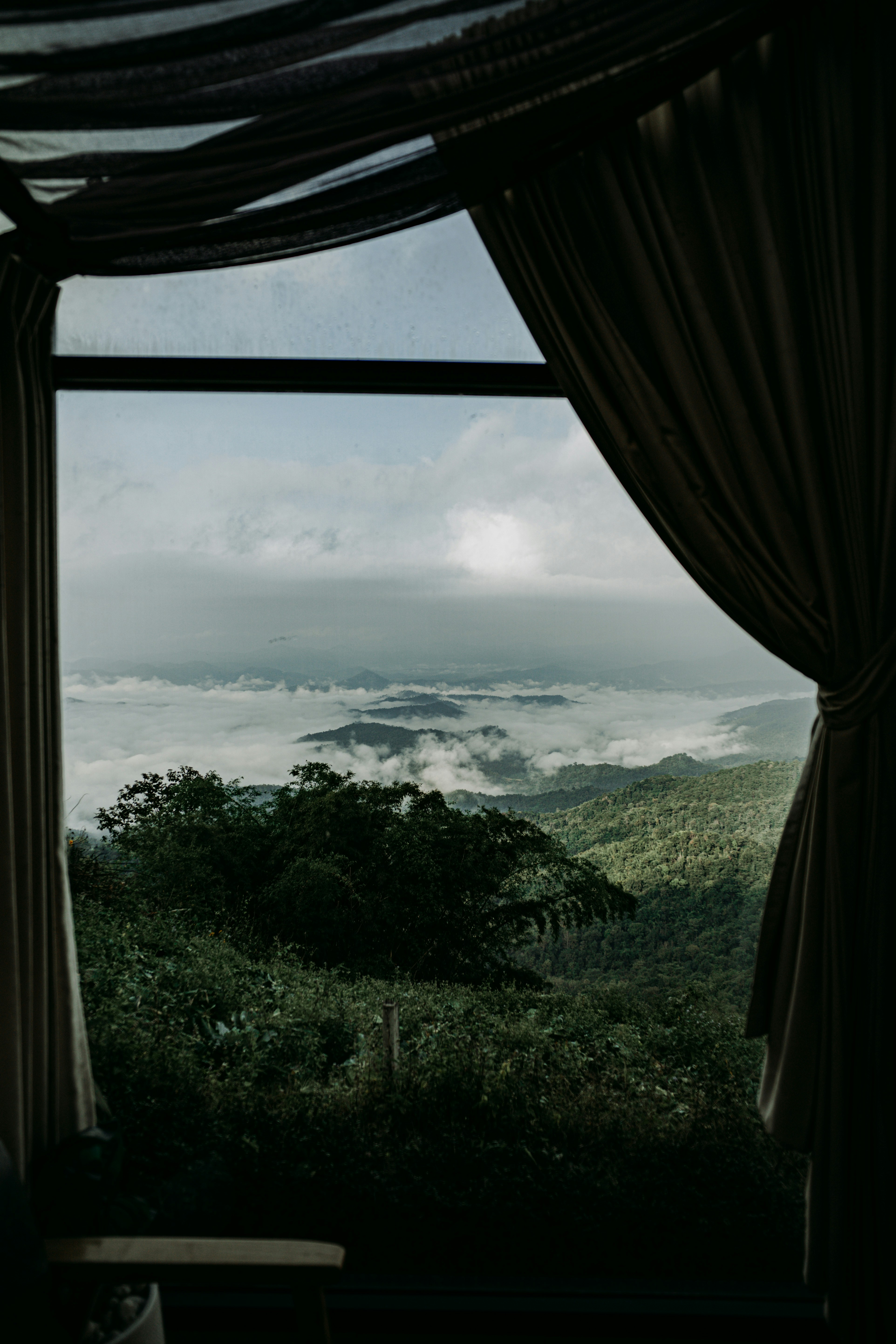 Window to the Valley: Curtains Frame a Misty Mountain View