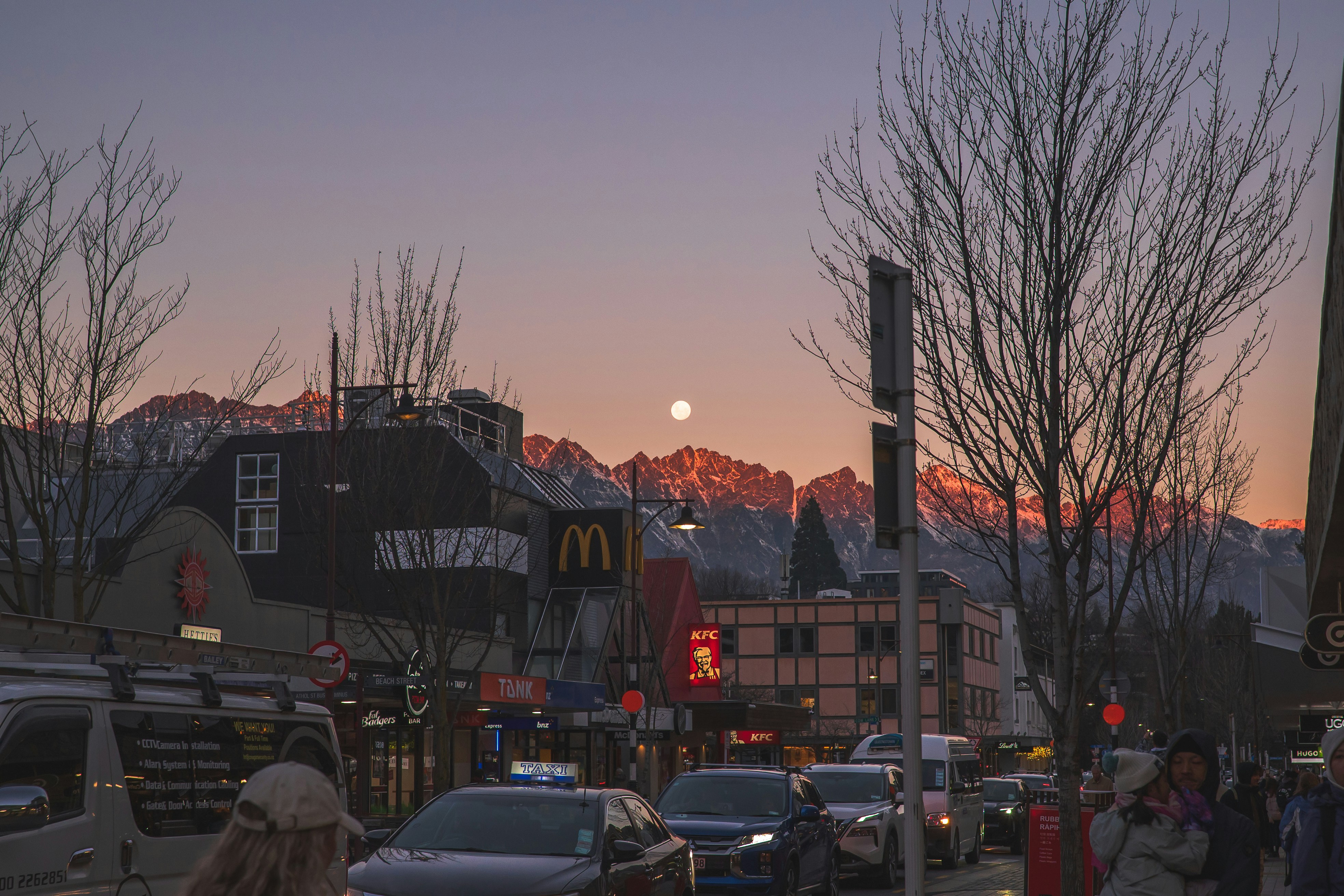 Moonrise Over a Bustling Main Street at Dusk